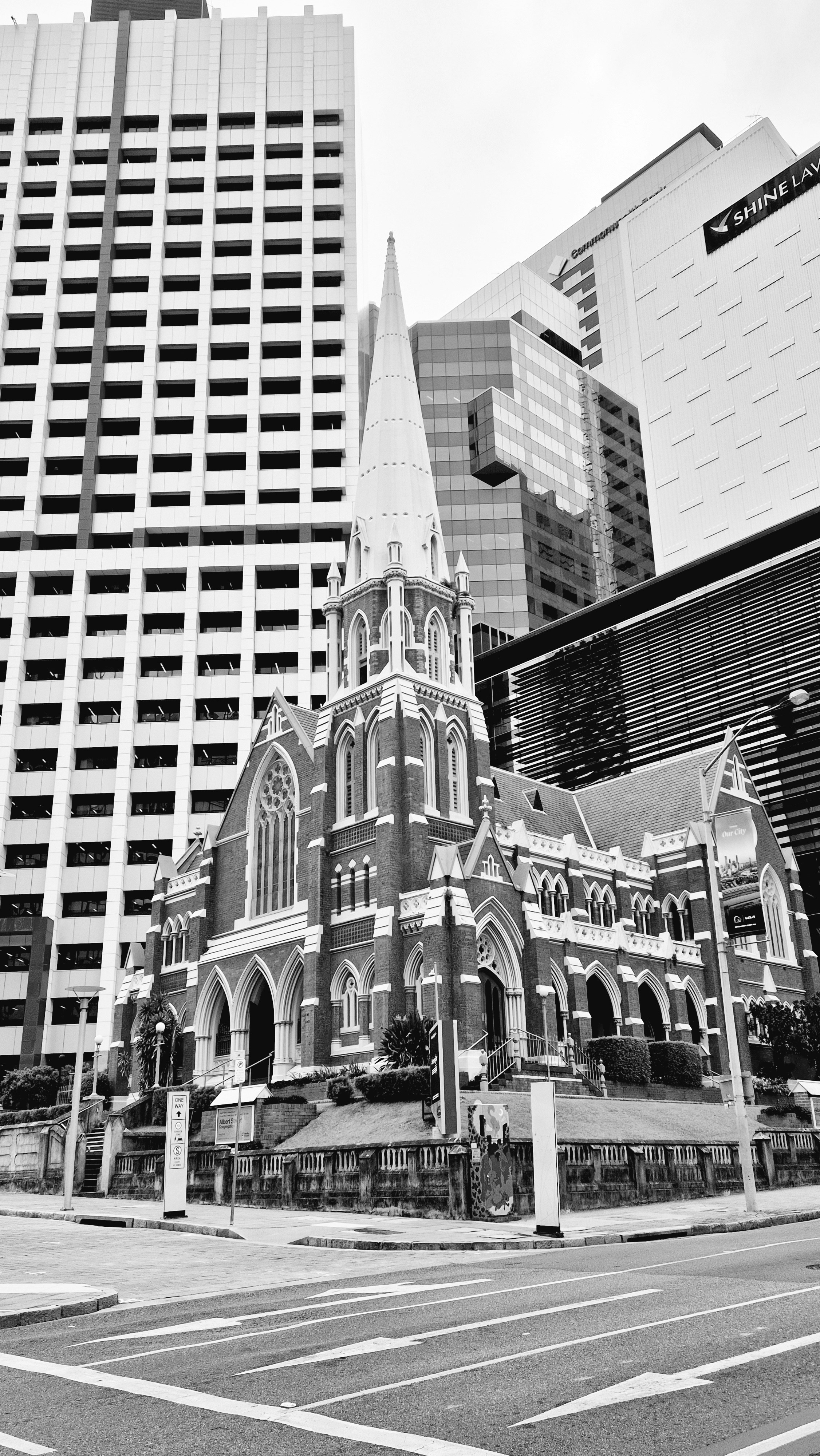 Black-and-white photograph of a Gothic church juxtaposed with towering modern buildings.