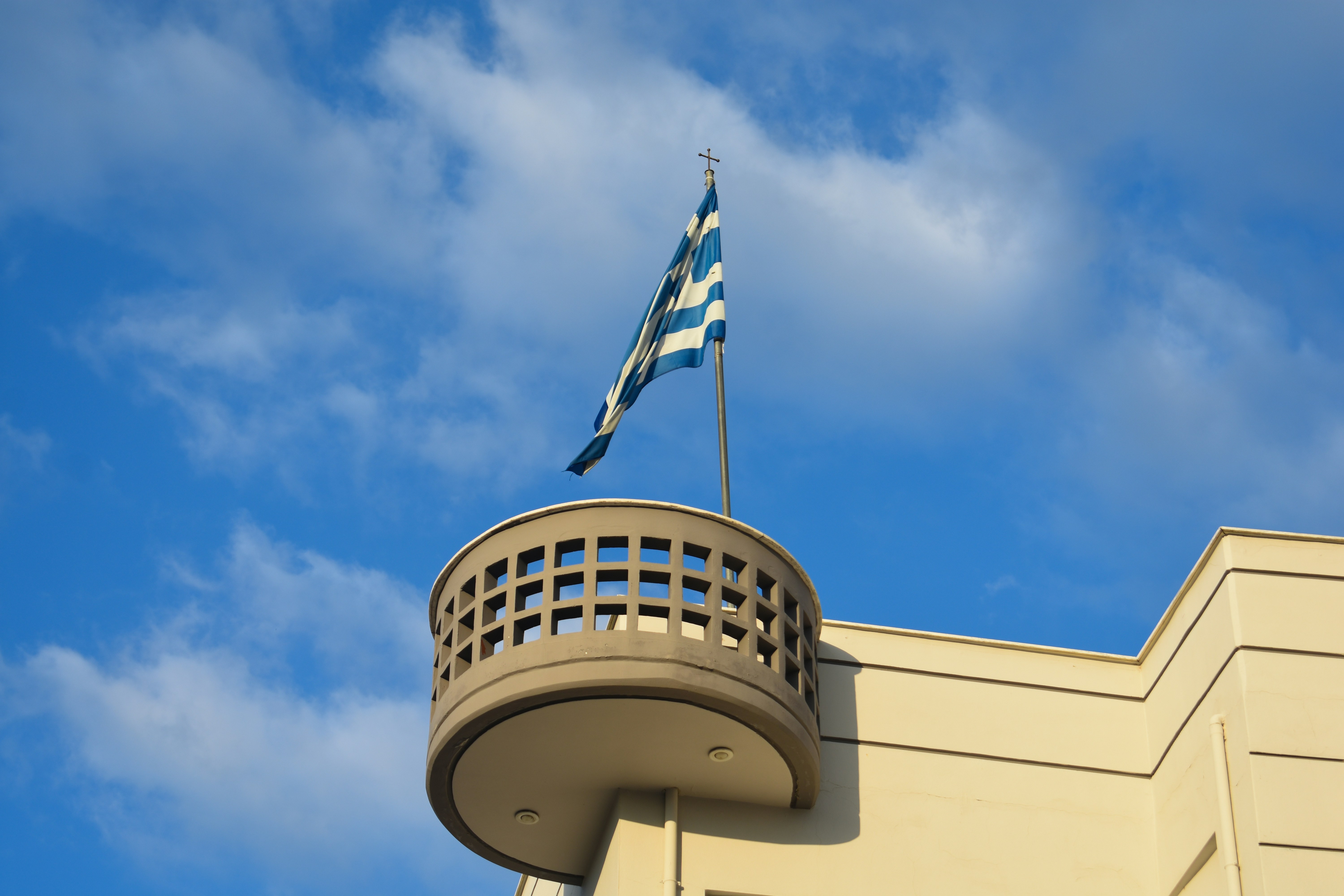 Flag on a Curved Balcony Over a Sunlit Beige Facade