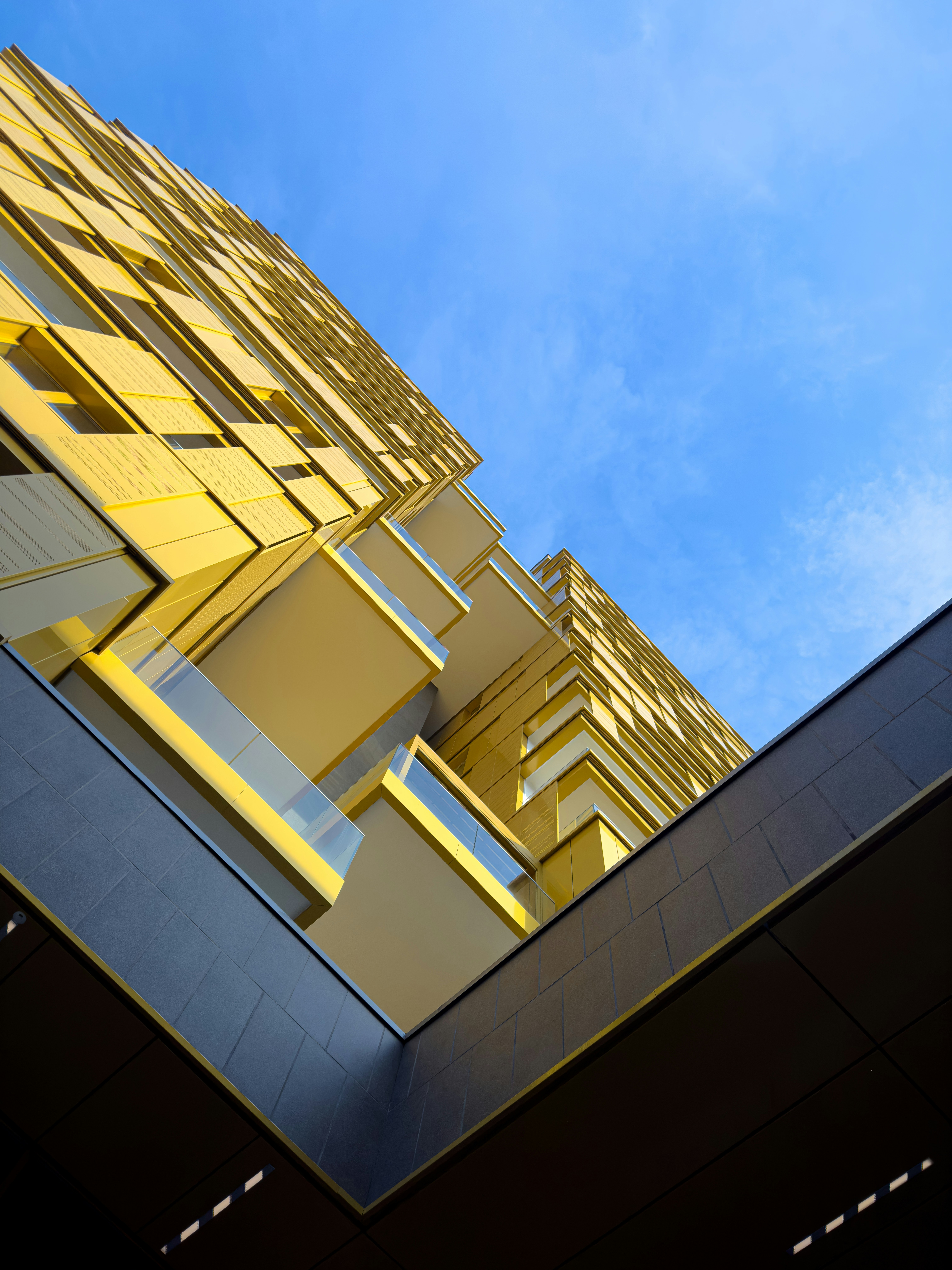 A tall yellow building with a blue sky in the background photo – Free ...