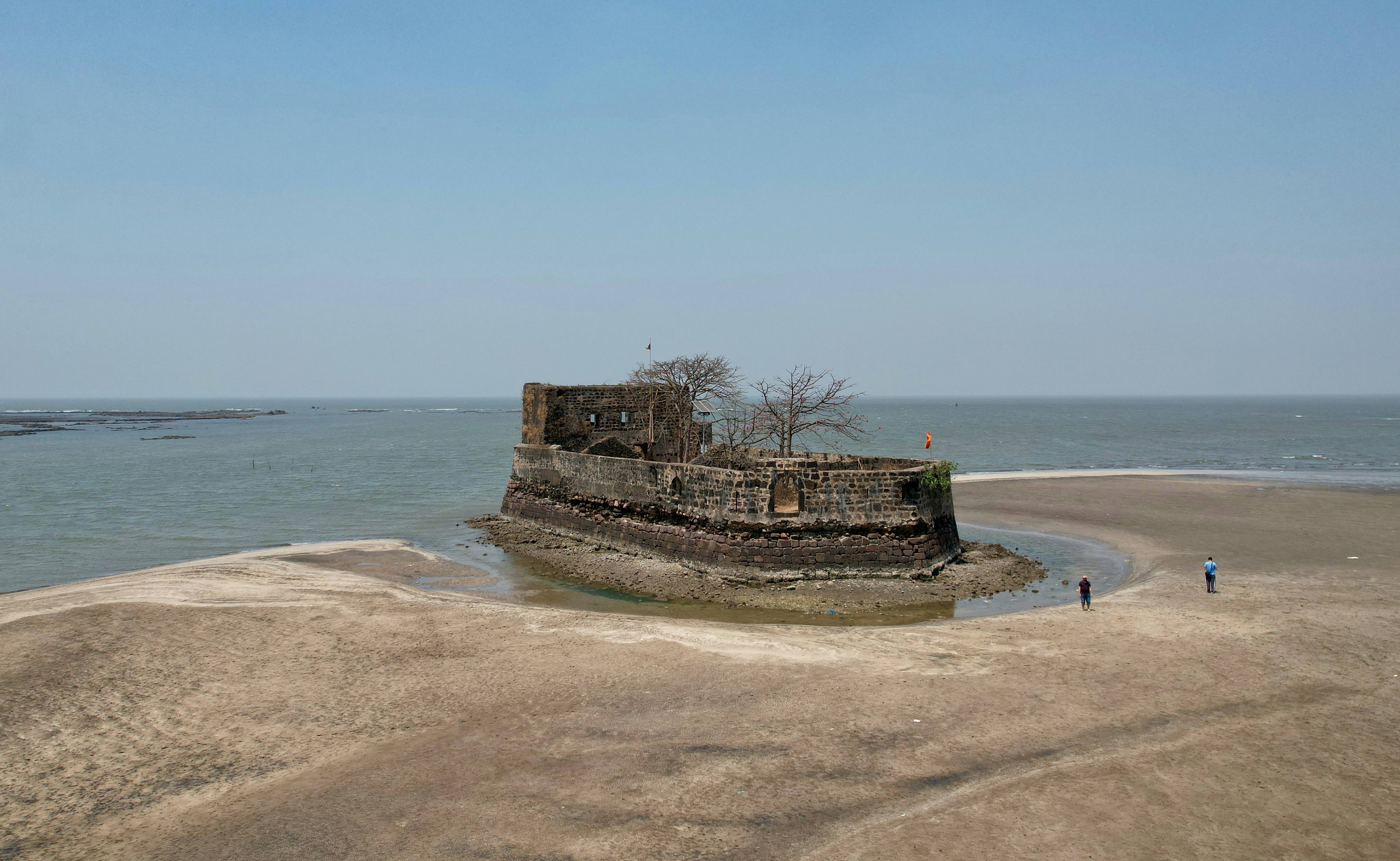 Kelva Fort, situated in the village of Kelva in Maharashtra, India, is a historical fort believed to have been constructed during the Portuguese rule in the 16th century. It features typical Portuguese architecture, characterized by sturdy stone walls and corner bastions. Located near the Arabian Sea, the fort offers panoramic views and is surrounded by lush greenery. Visitors can explore the fort's rectangular layout and towers, and also enjoy activities such as beachcombing and swimming at the nearby Kelva Beach.