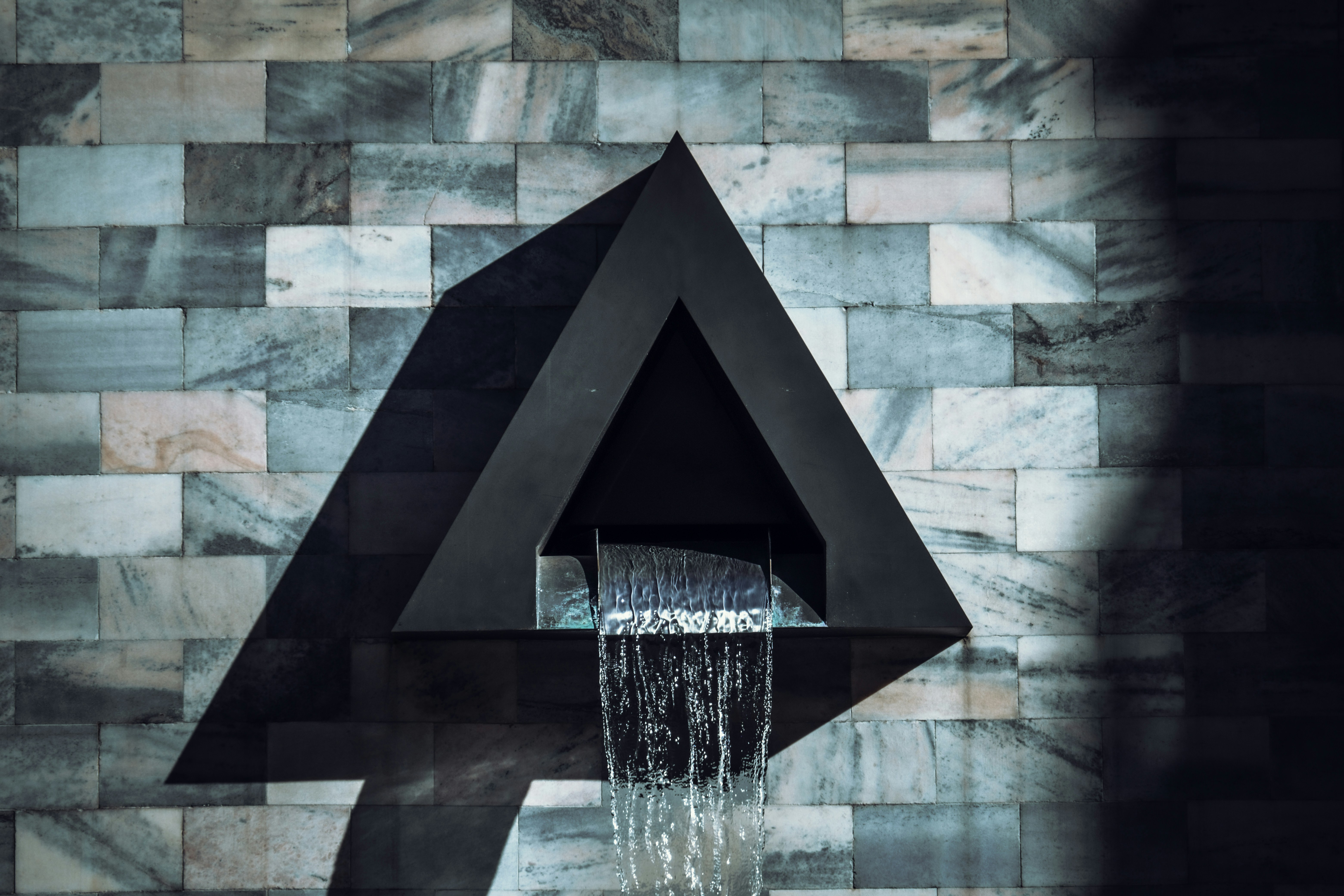 Triangular Portal: Water Cascades from a Dark Prism in a Mosaic Wall