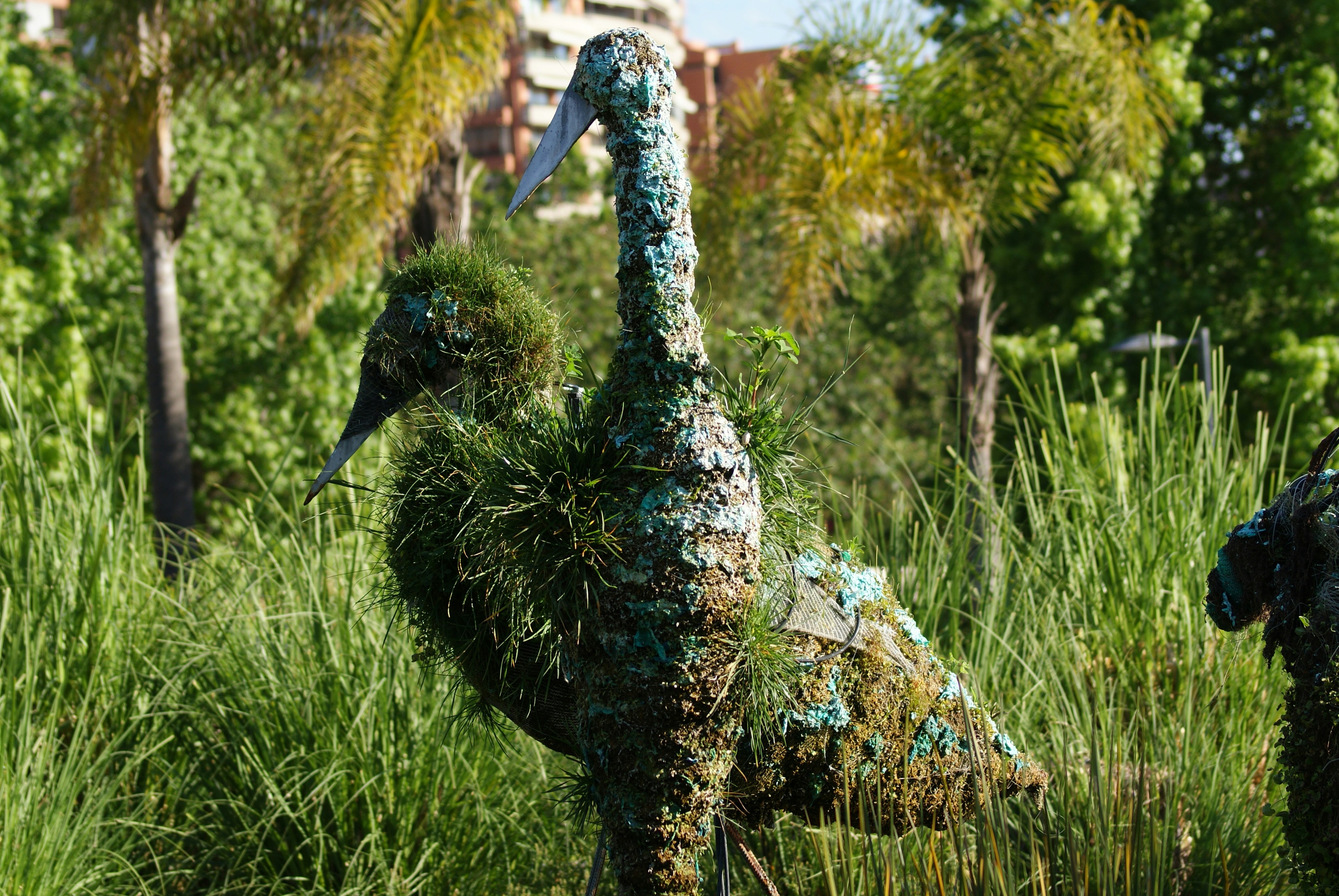 Verdant Sentinels: Moss-Covered Herons Guard a Sunlit Garden