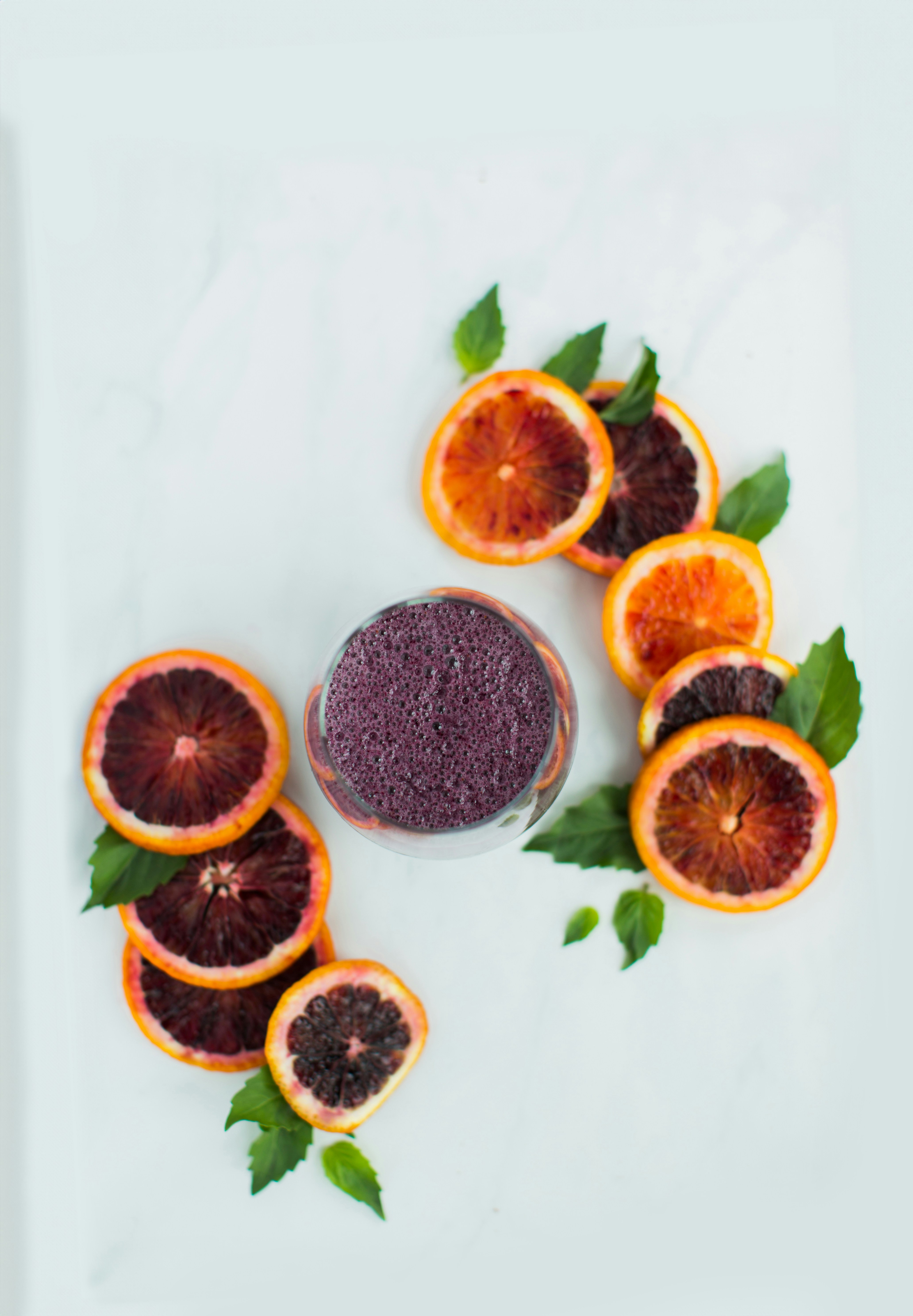 Citrus Ring Framing a Violet Smoothie on a Pale Canvas