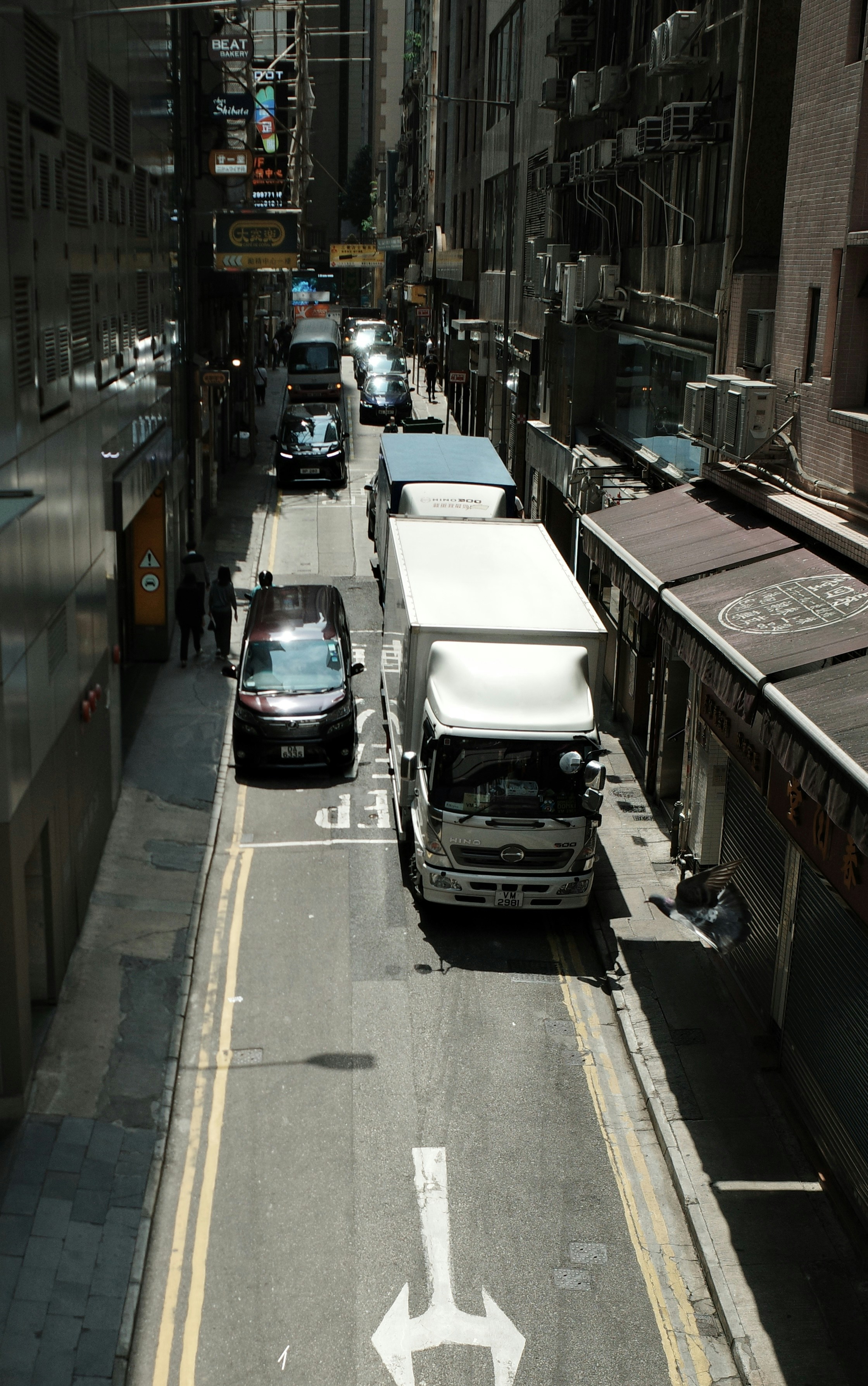Vertical Alley Run: A White Truck Leads Through a Narrow City Street