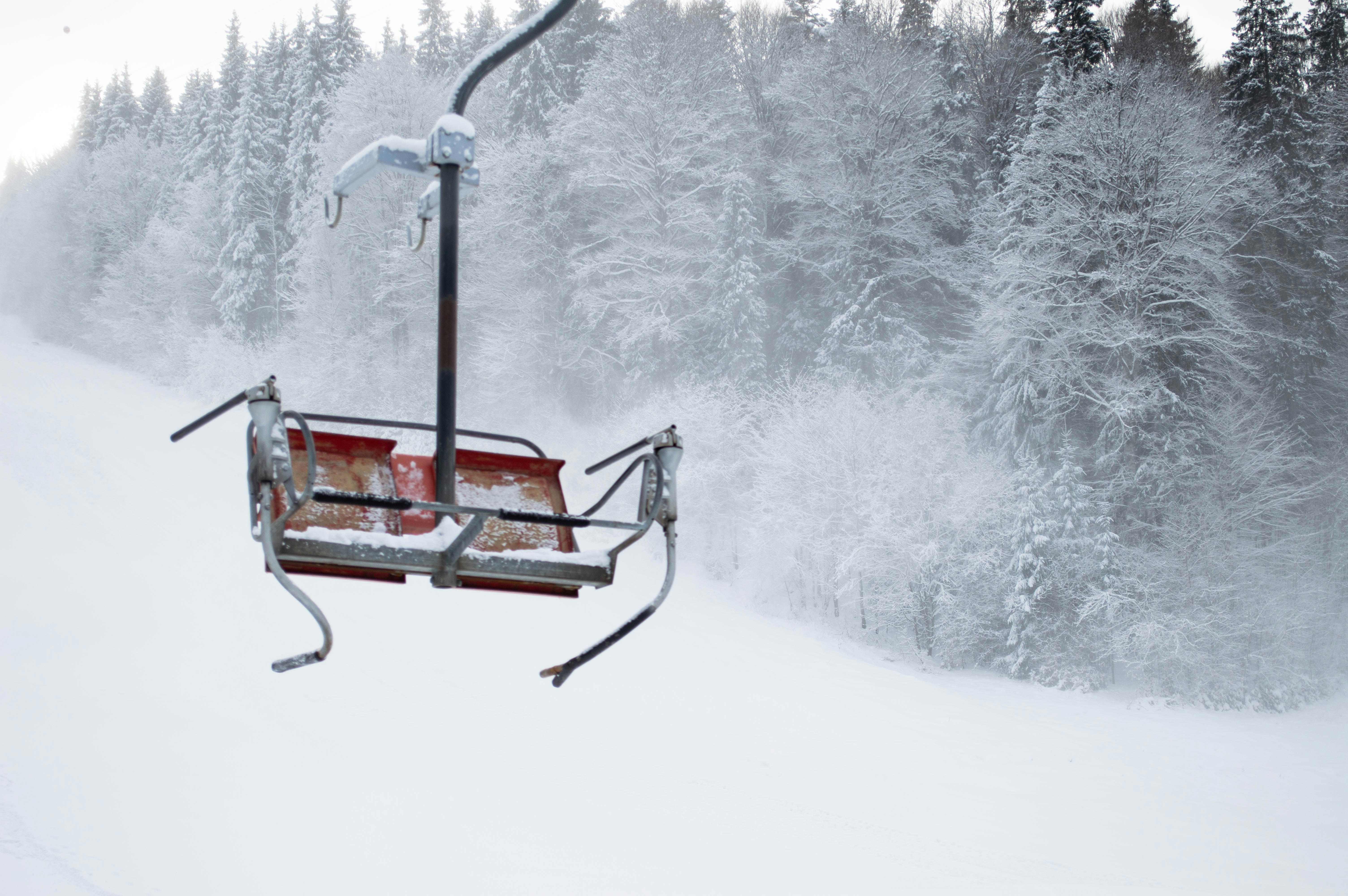 Lone ski-lift chair drifting through a winter hush beneath snow-laden pines