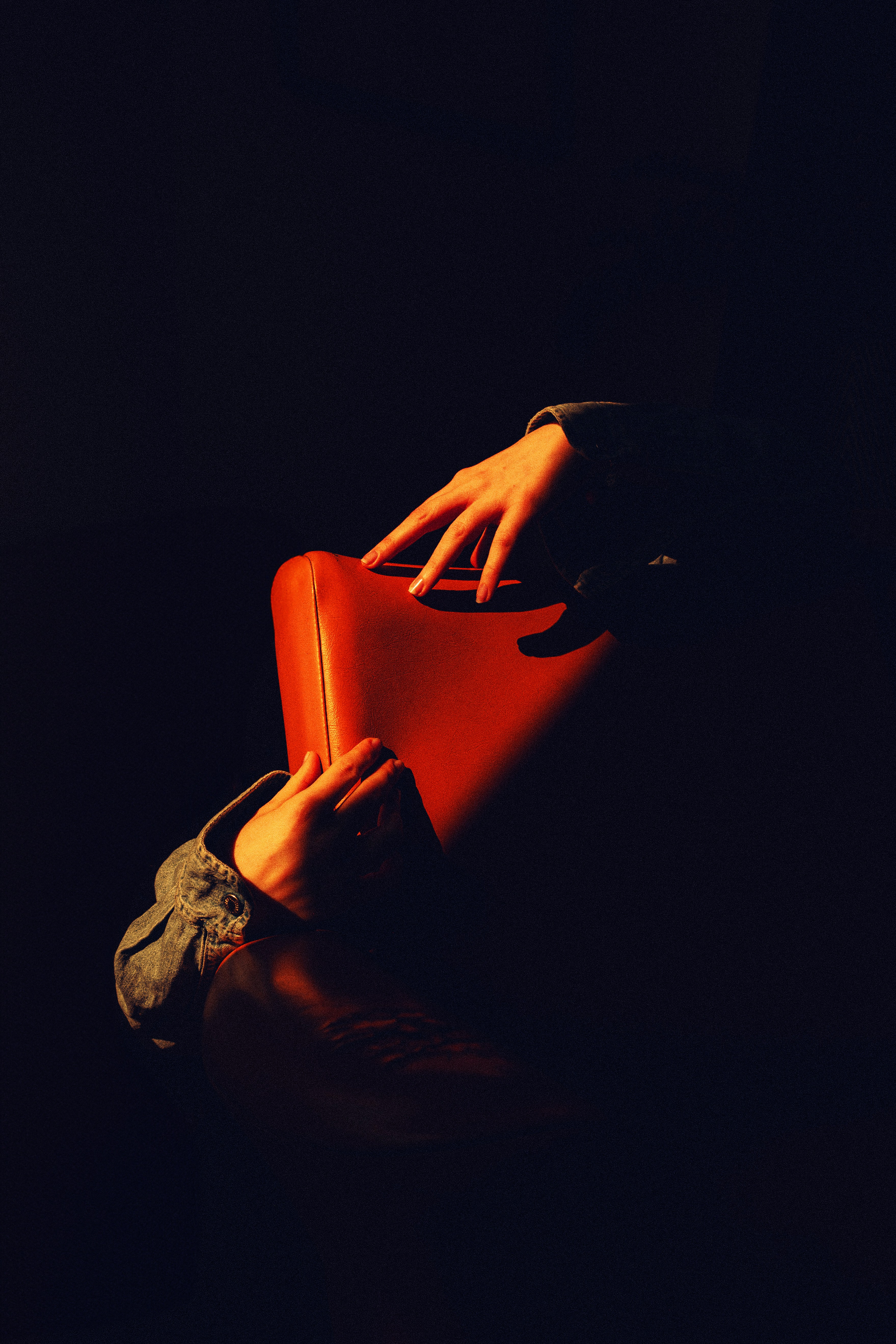 Cradled in Velvet Shadows: A Red Leather Clutch Lit by a Narrow Beam