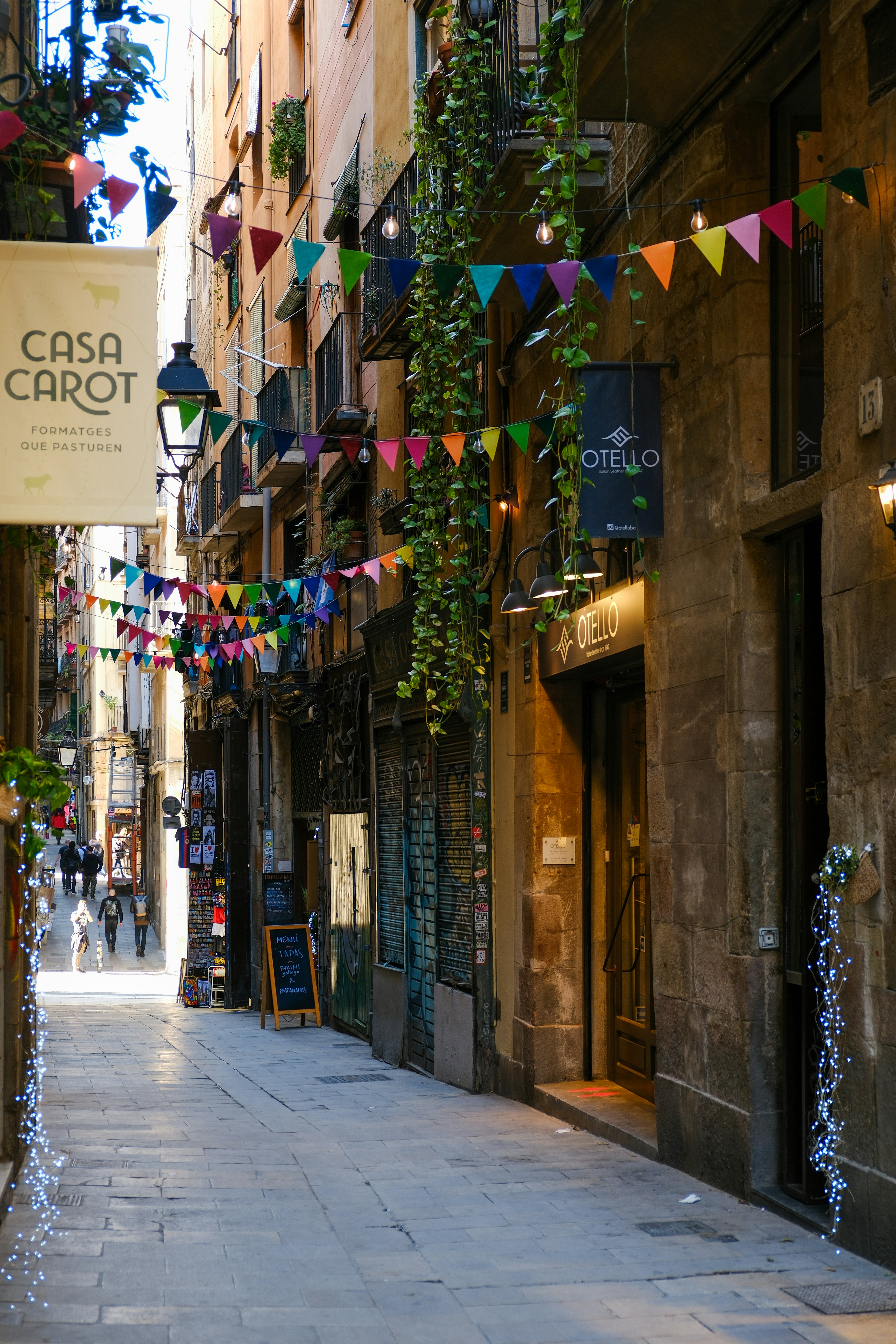 Colorful festival banners drape a sunlit alley between stone facades