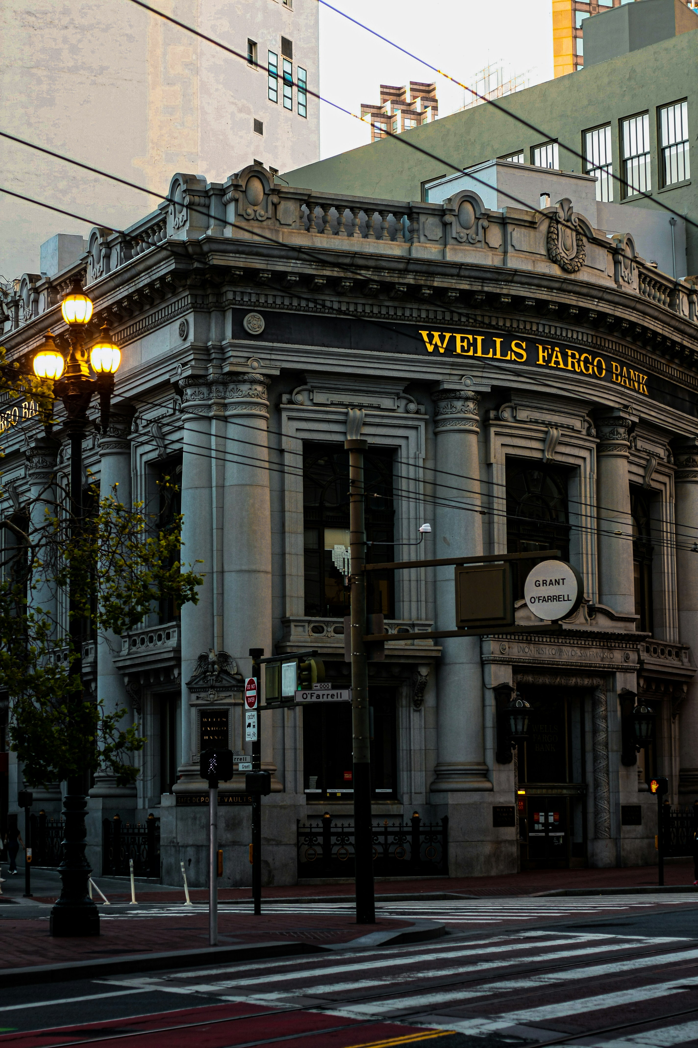 As the sun begins to set, casting a golden hue on the city, the grandiose façade of the Wells Fargo Bank stands as a monument to the financial history and architectural grandeur of San Francisco. The elegant stone columns and intricate details speak of a bygone era, juxtaposed against the backdrop of modern urban life. This photograph, with its interplay of light and shadow, is an ideal addition to articles discussing the evolution of finance or the architectural tapestry of the city.
