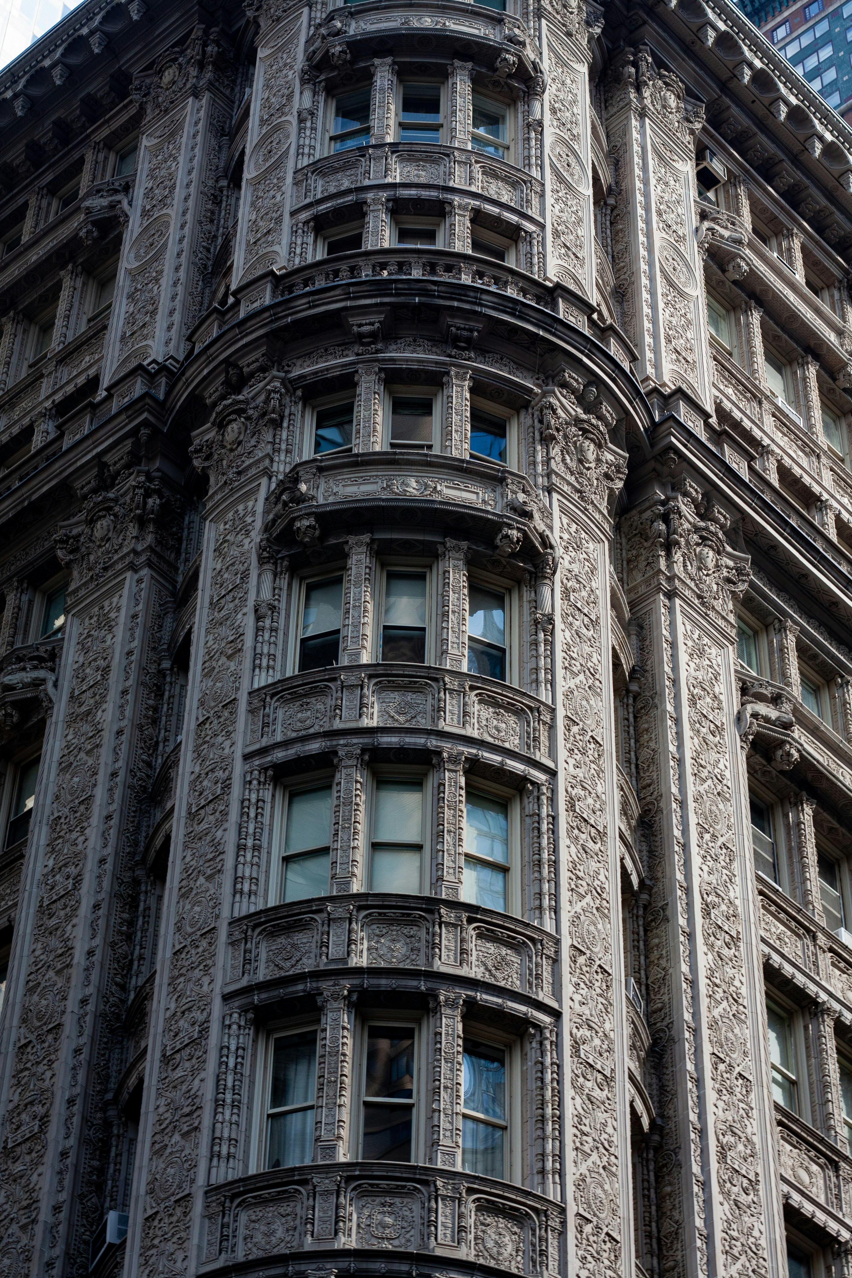 The photograph showcases the intricate beauty of classical architecture, focusing on the ornate facades of a historic building. The elaborate stone carvings and stately bay windows speak to an era of craftsmanship and detail, standing tall against the blue of the sky. This image captures the grandeur of the urban landscape, a perfect complement to discussions about architectural heritage, design, or the aesthetic evolution of city buildings in your blog articles