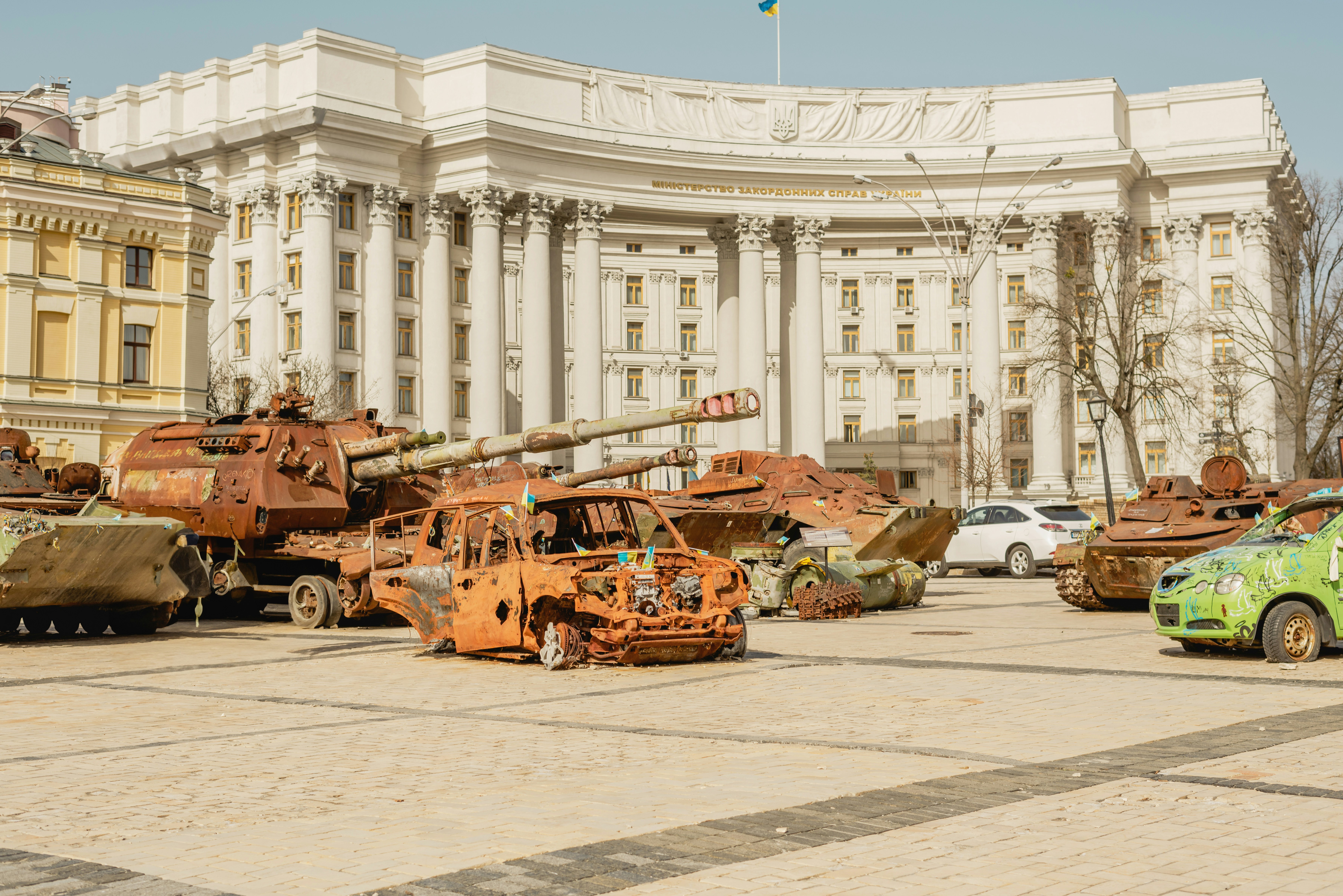 A group of tanks and cars parked in front of a building photo – Free ...