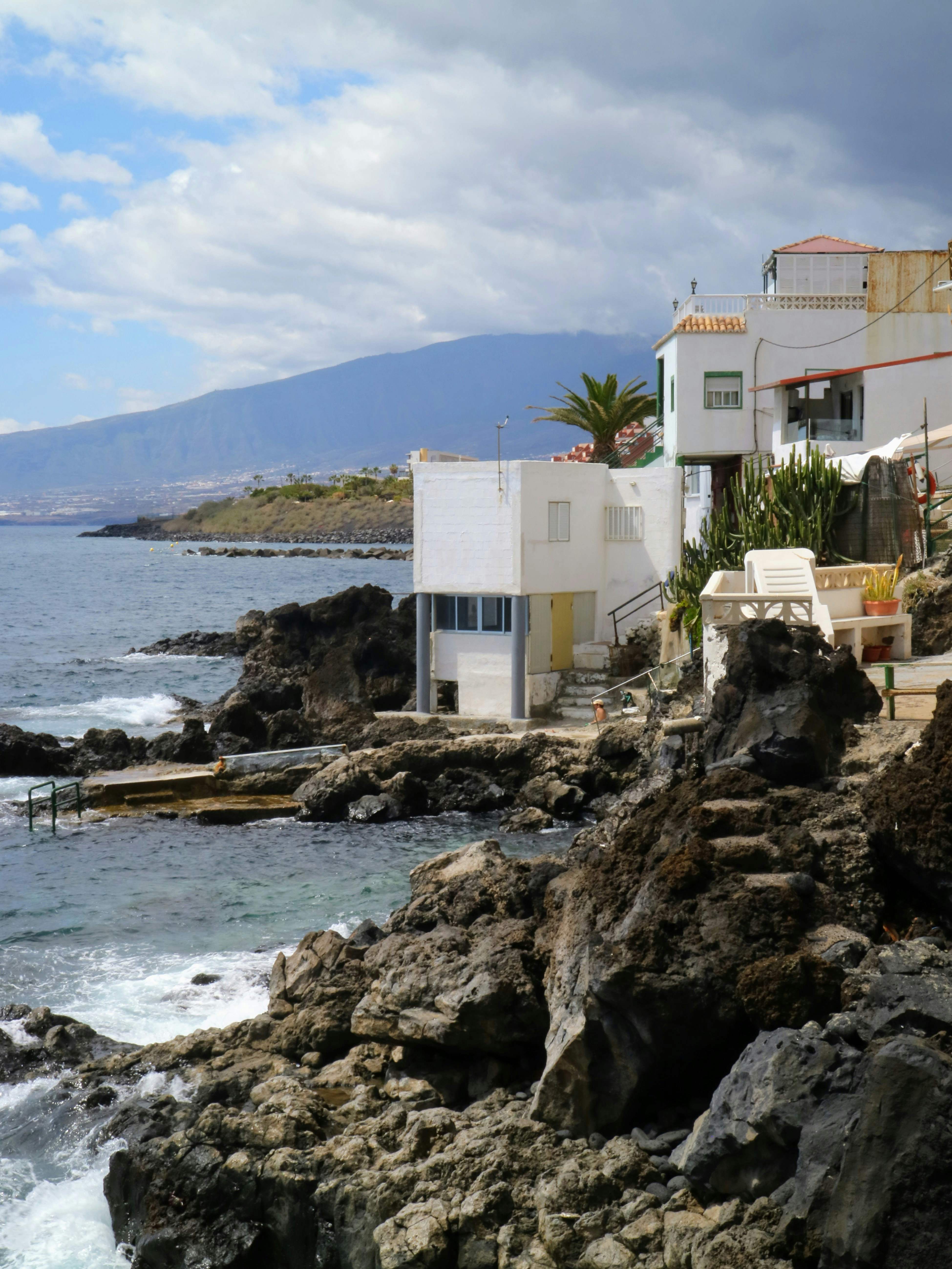 Cliffside Clusters: White-Washed Homes Over Volcanic Rocks