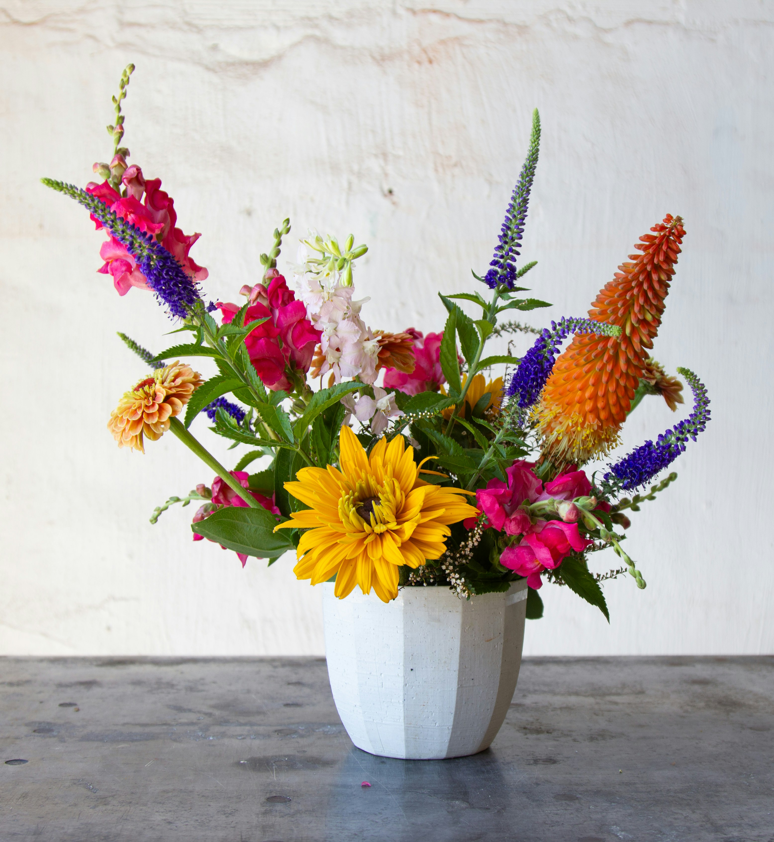 Festival of Color: Sunflowers and Spires in a Pale Ceramic Vase