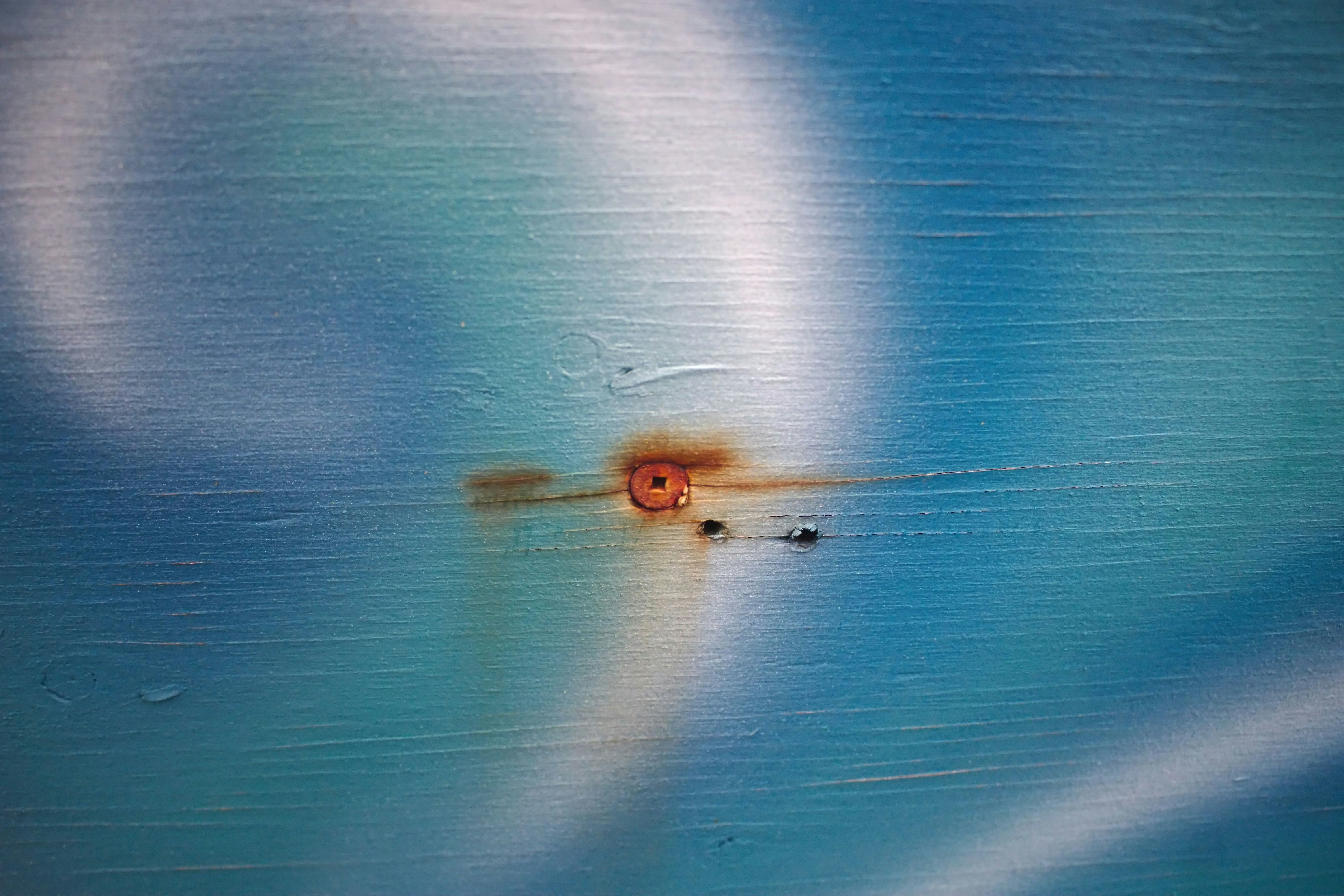 Ceramic Blue: a weathered panel with a rusted dot and soft arc of light