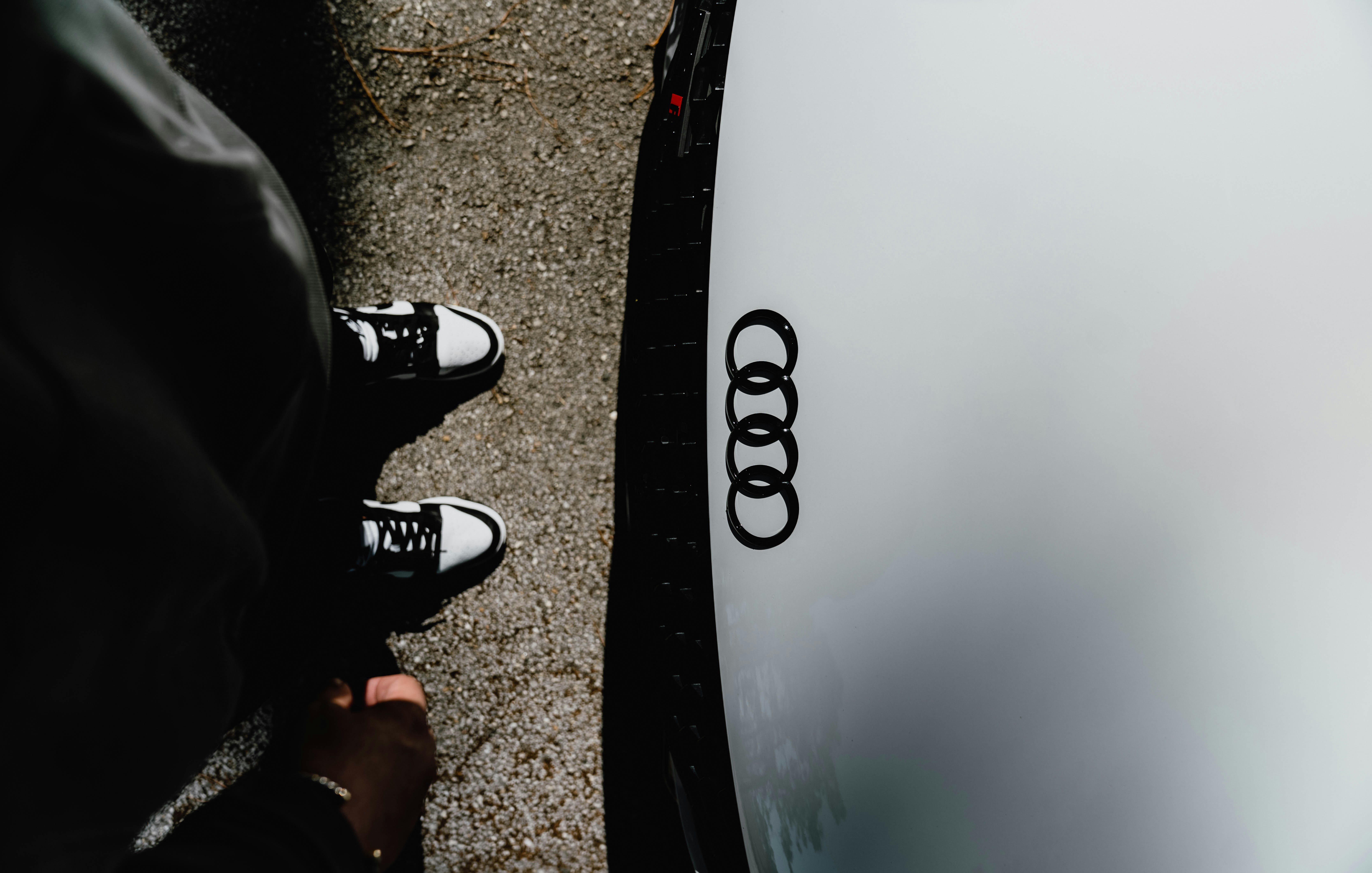 Footwear and Audi badge: a ground-level reflection of a parked luxury