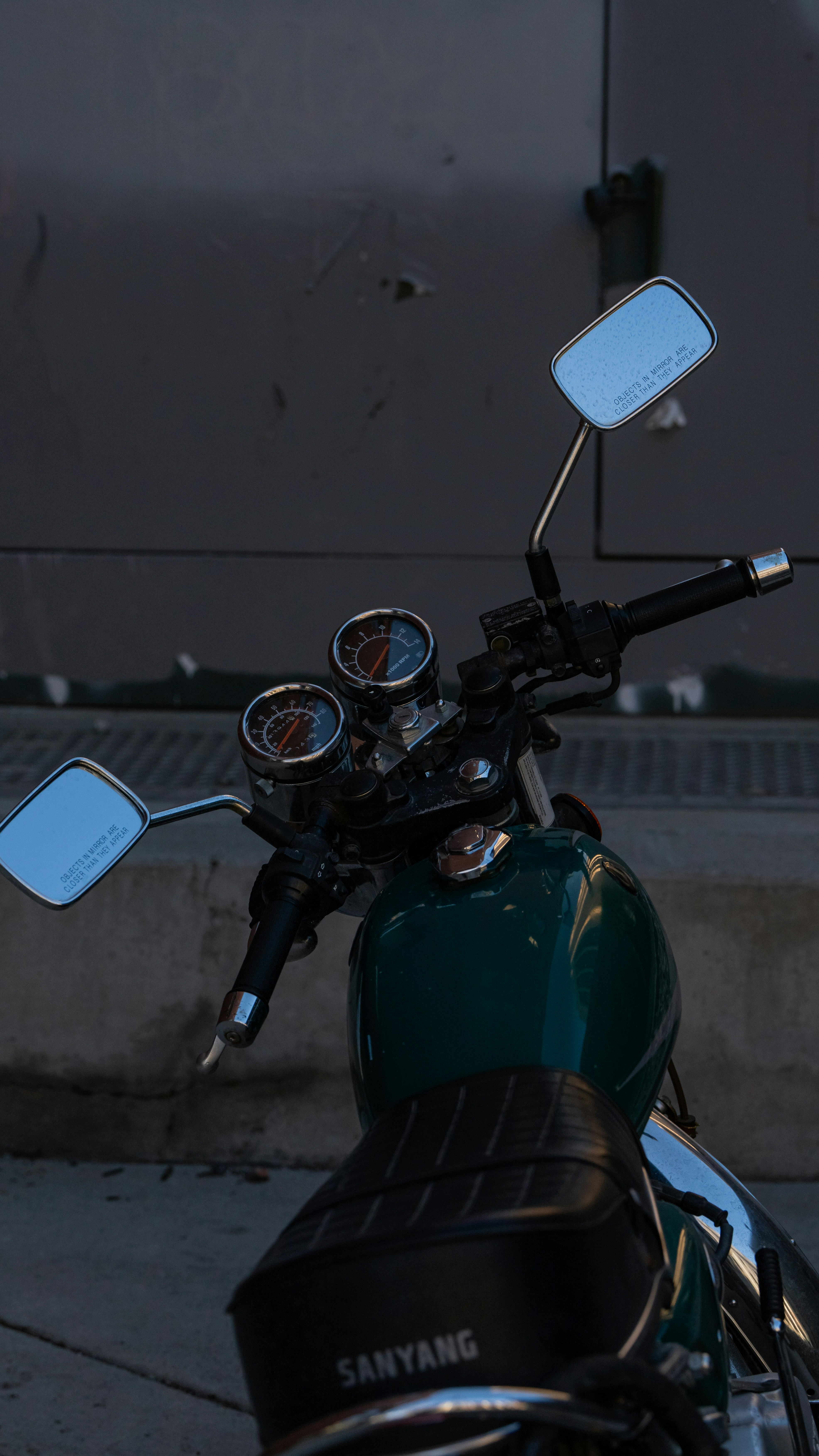 Teal Cockpit at Dusk: Reflections and Gauges on a Vintage Motorcycle