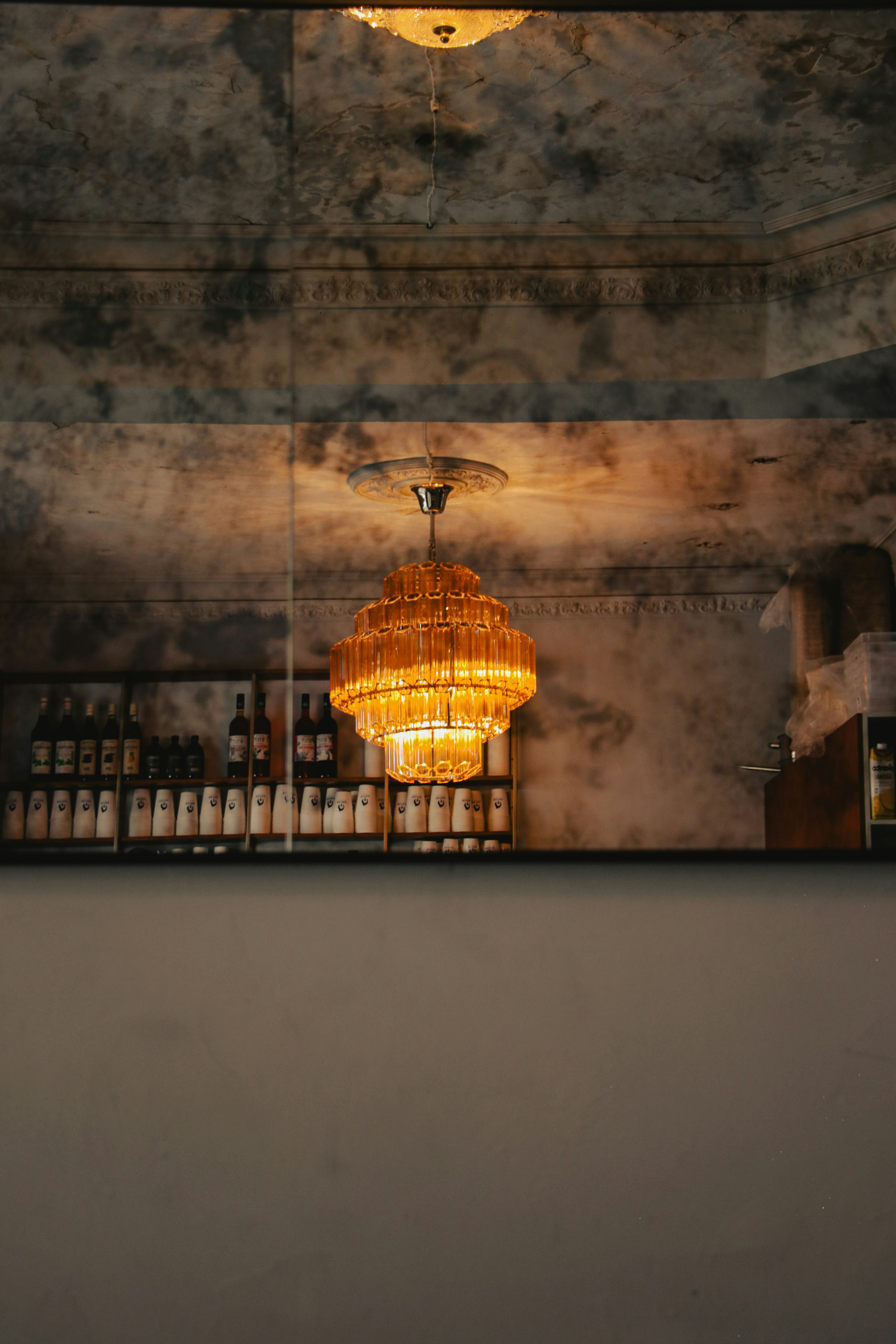 Golden Orb Over a Moody Bar: Amber Chandelier in a Weathered Room
