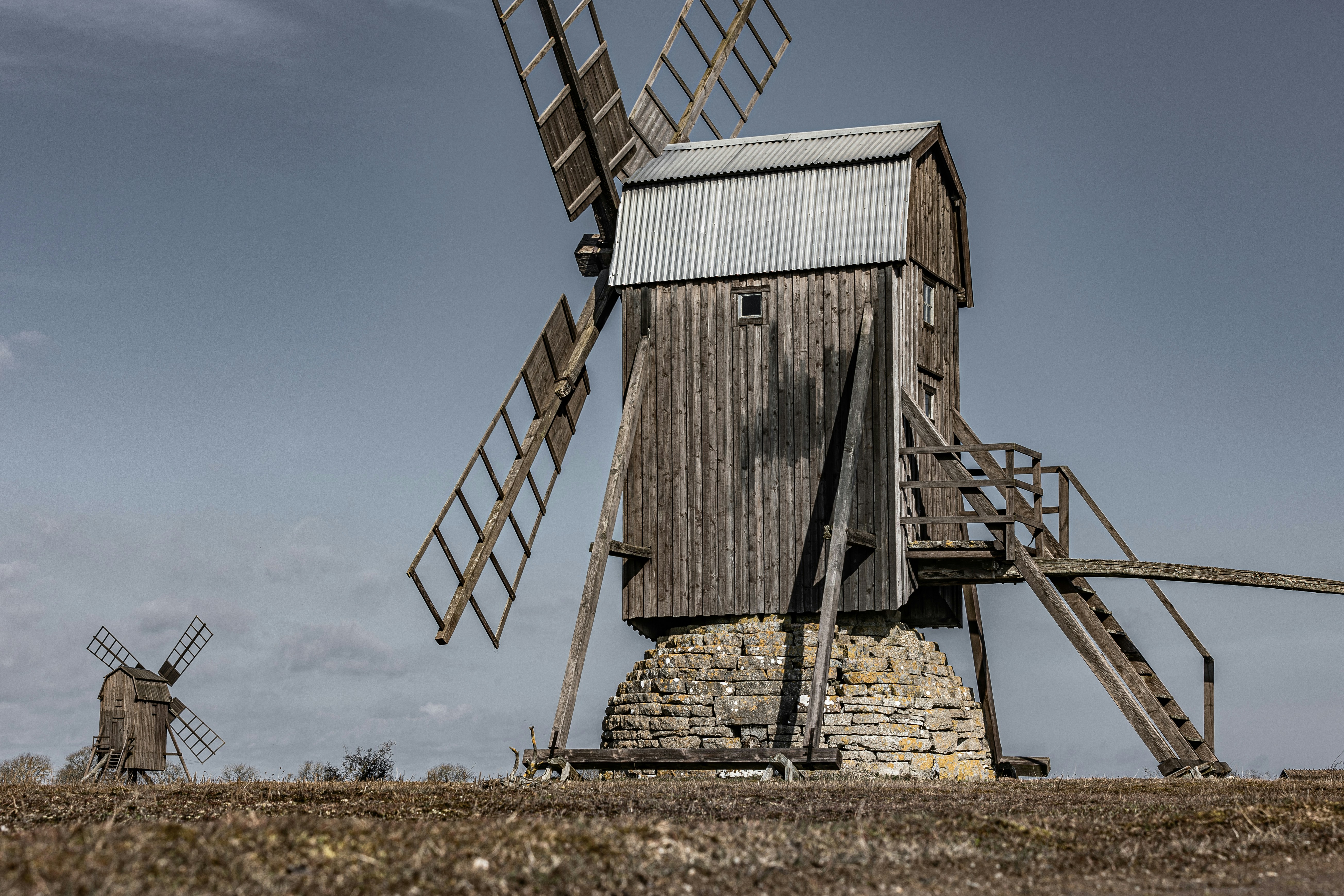 A wooden windmill sitting on top of a dry grass field photo – Free ...