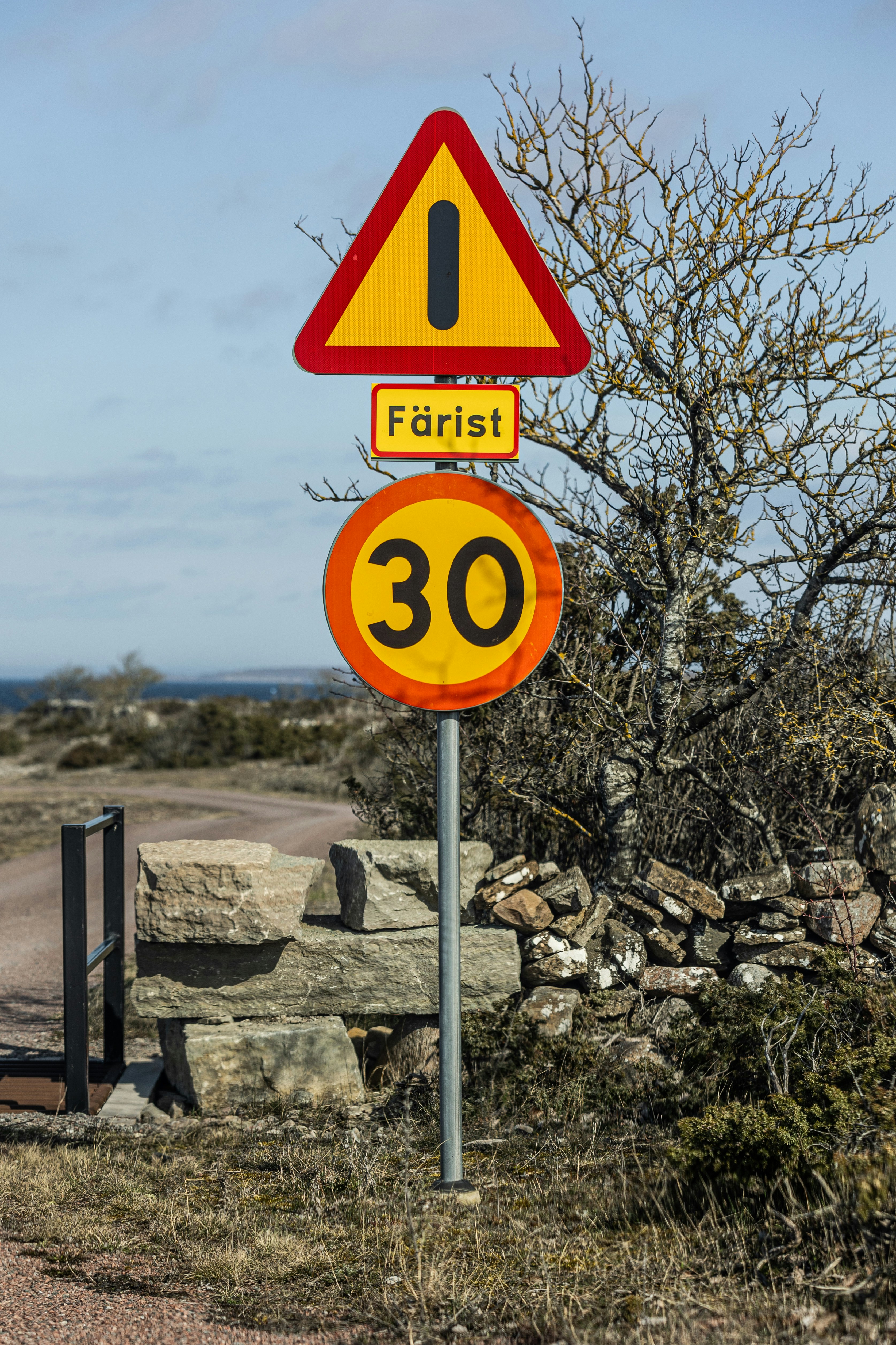 Three-Tier Road Sign by a Stone Wall in Quiet Light