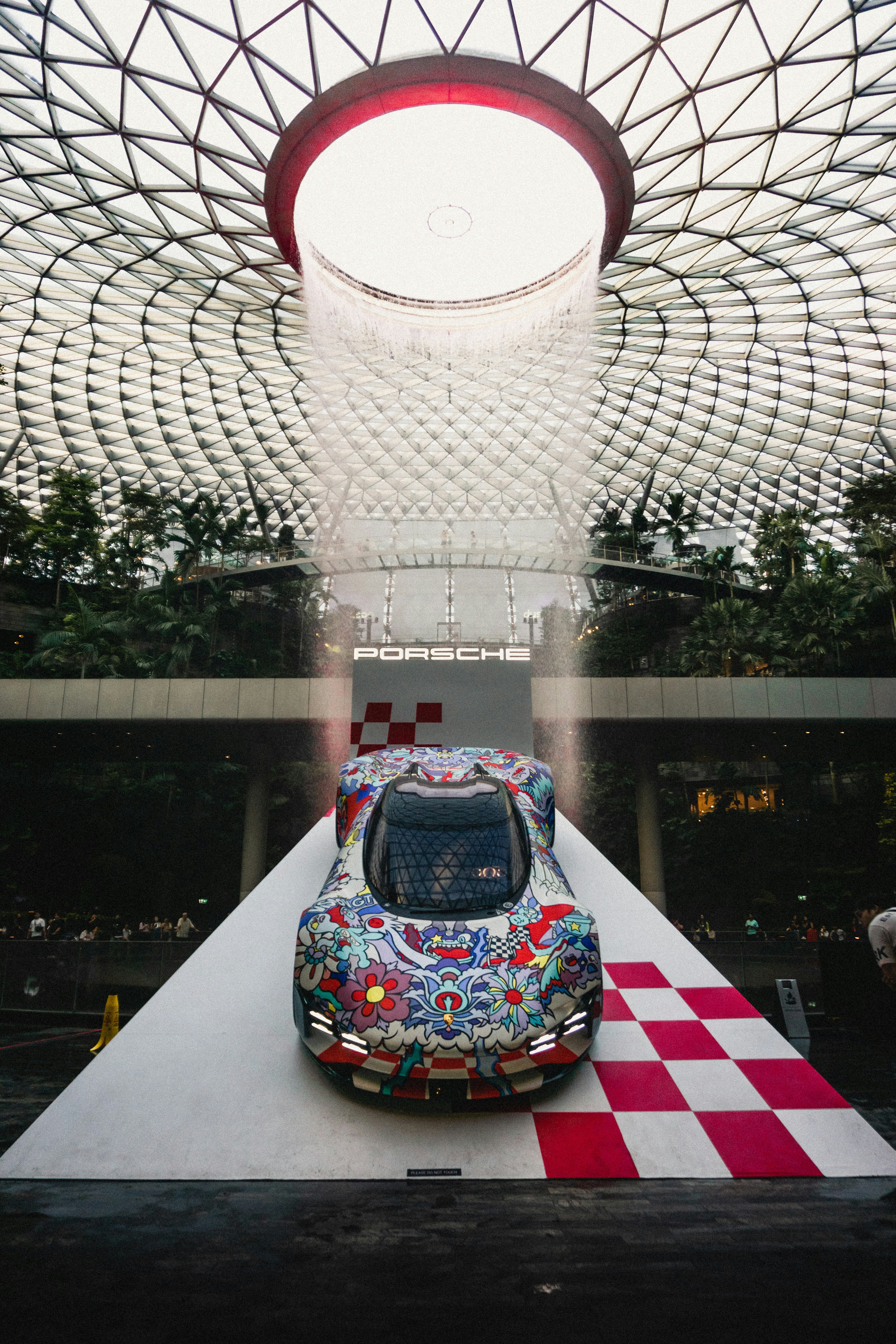Graffiti-Wrapped Porsche Rises on a Checkerboard Ramp Beneath a Geometric Glass Dome