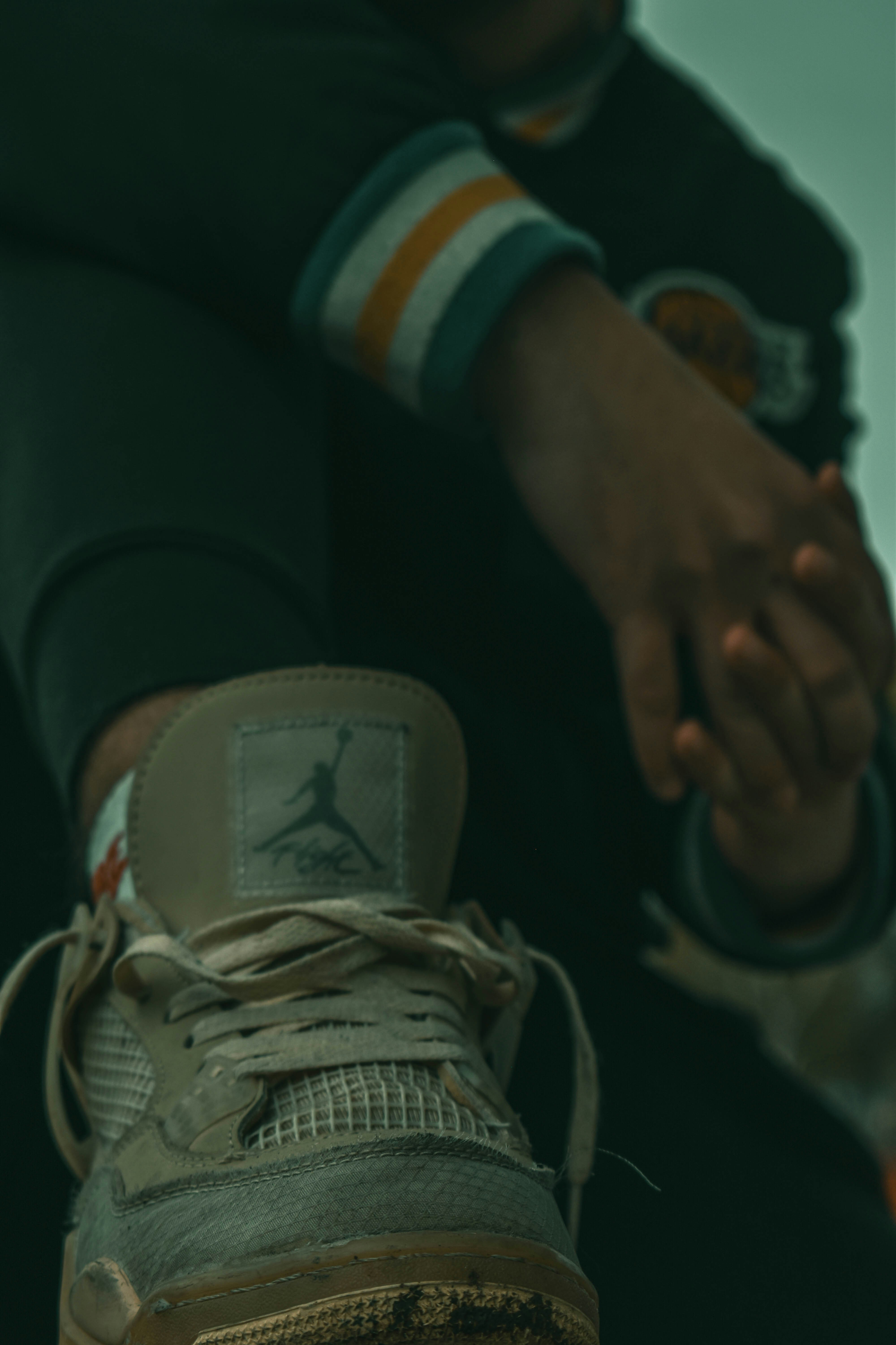 Close-up of a sneakered foot with hands clasped in the background