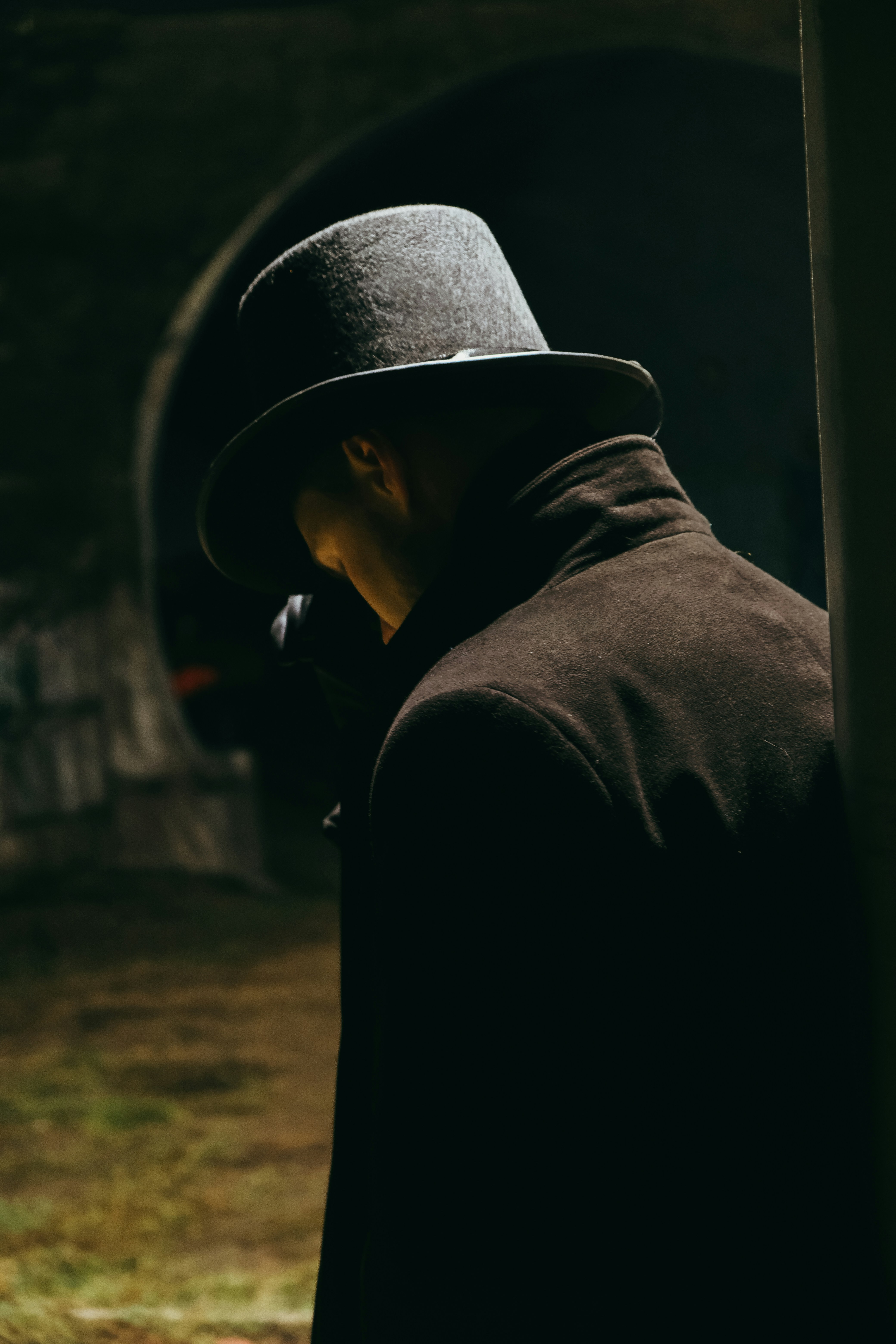 A man in a hat and coat standing next to a pipe photo – Free Park Image ...
