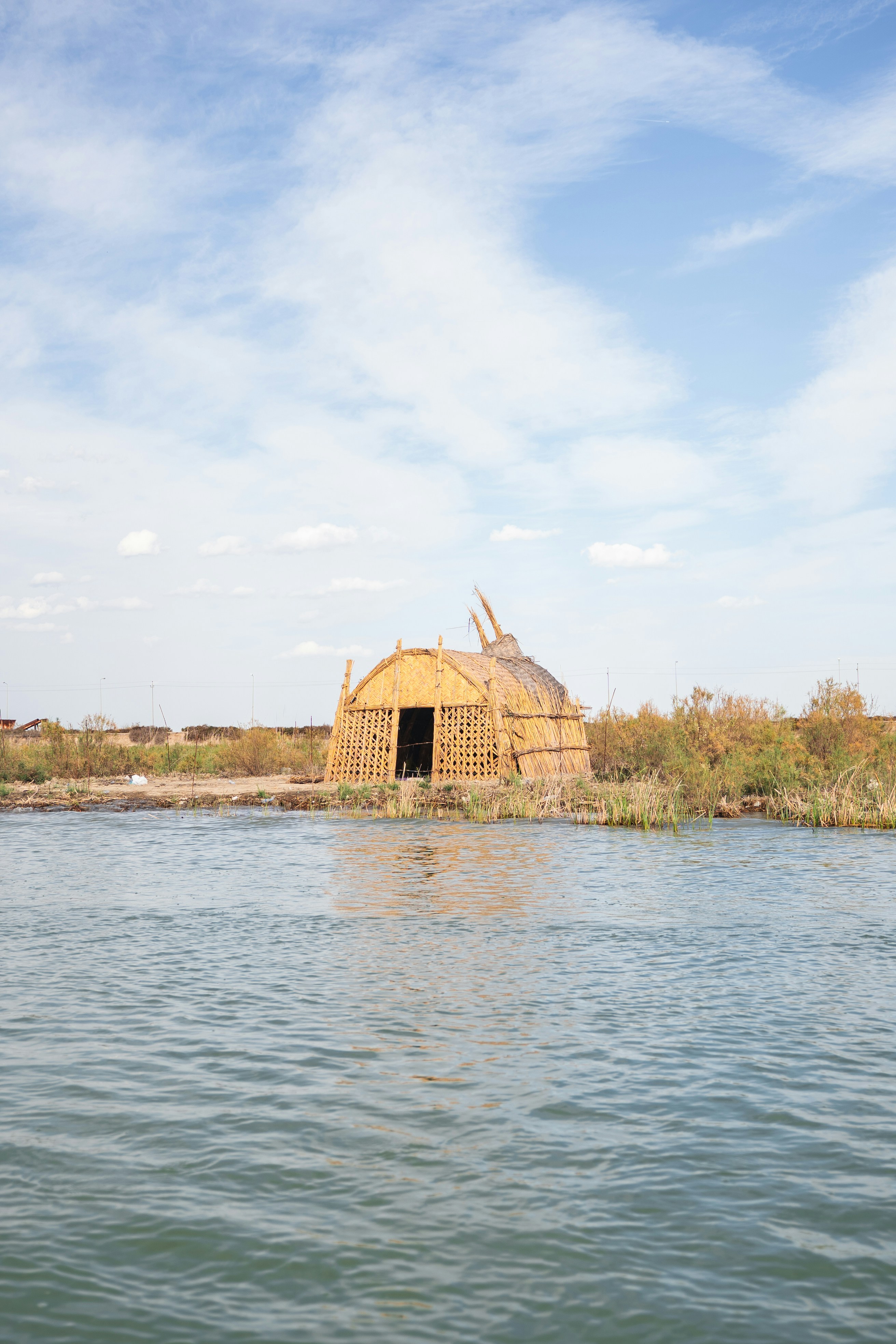 A house made out of straw sitting on top of a lake photo – Free Iraq ...