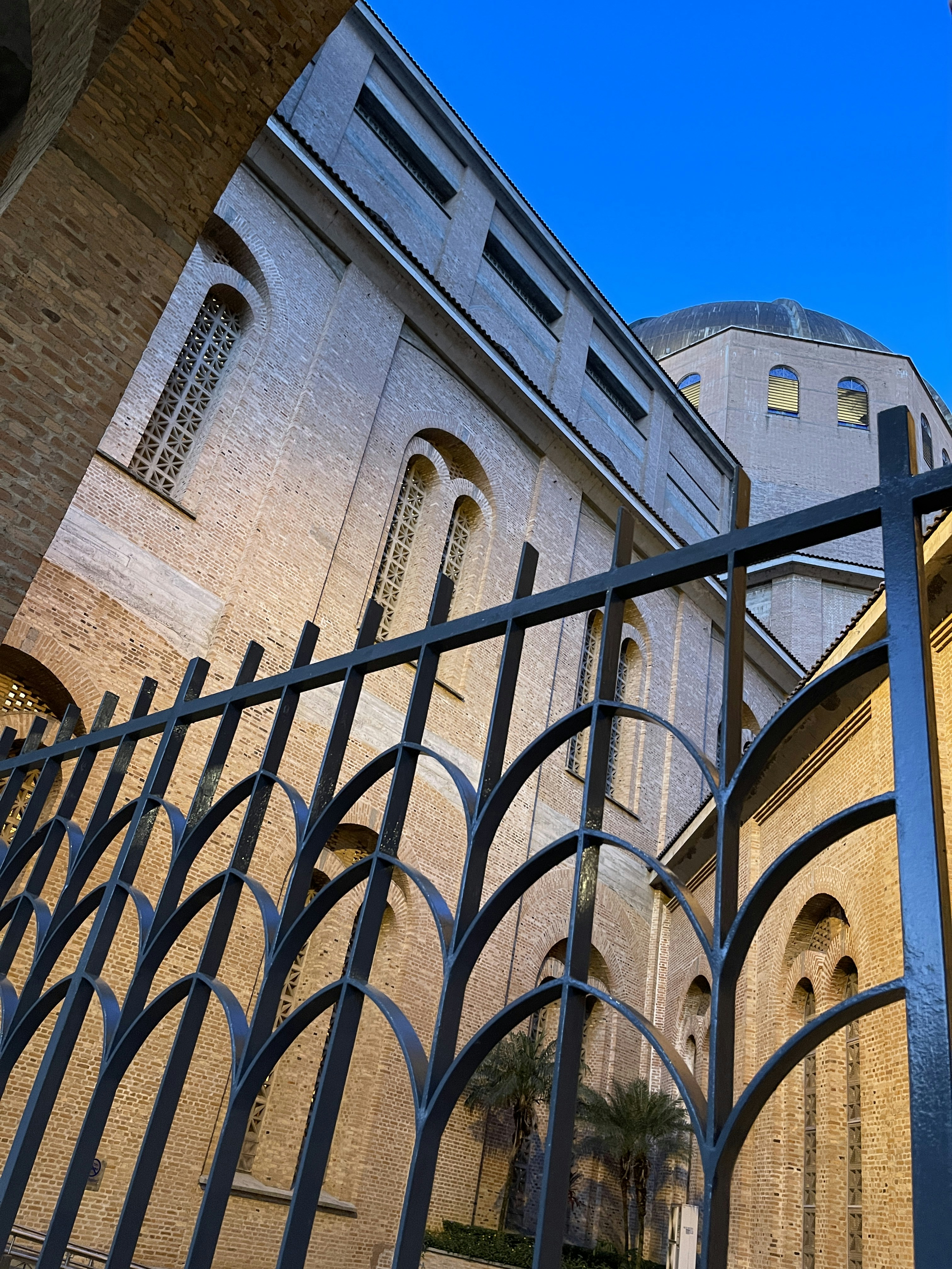 Arched Brick Facade Framed by Wrought-Iron Curves Under a Cerulean Sky