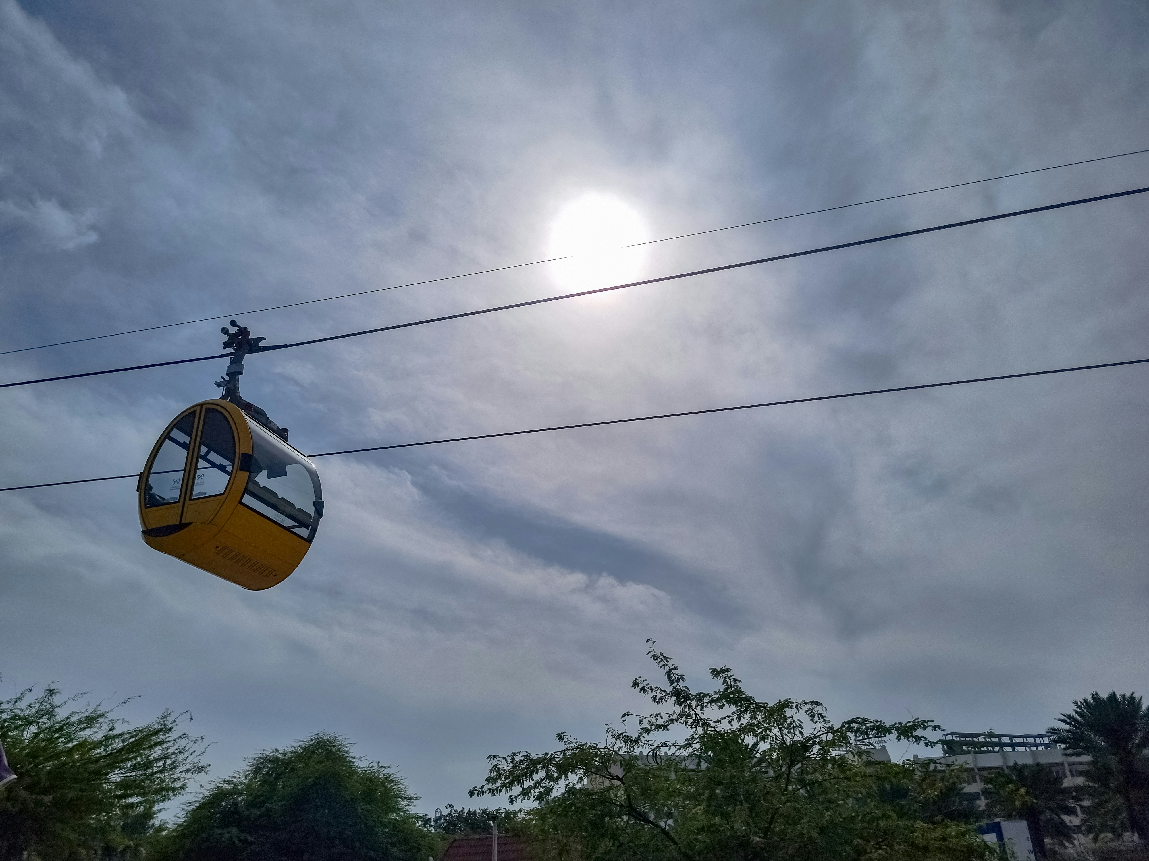 Sunlit Yellow Gondola Drift Across a Cloud-Washed Sky