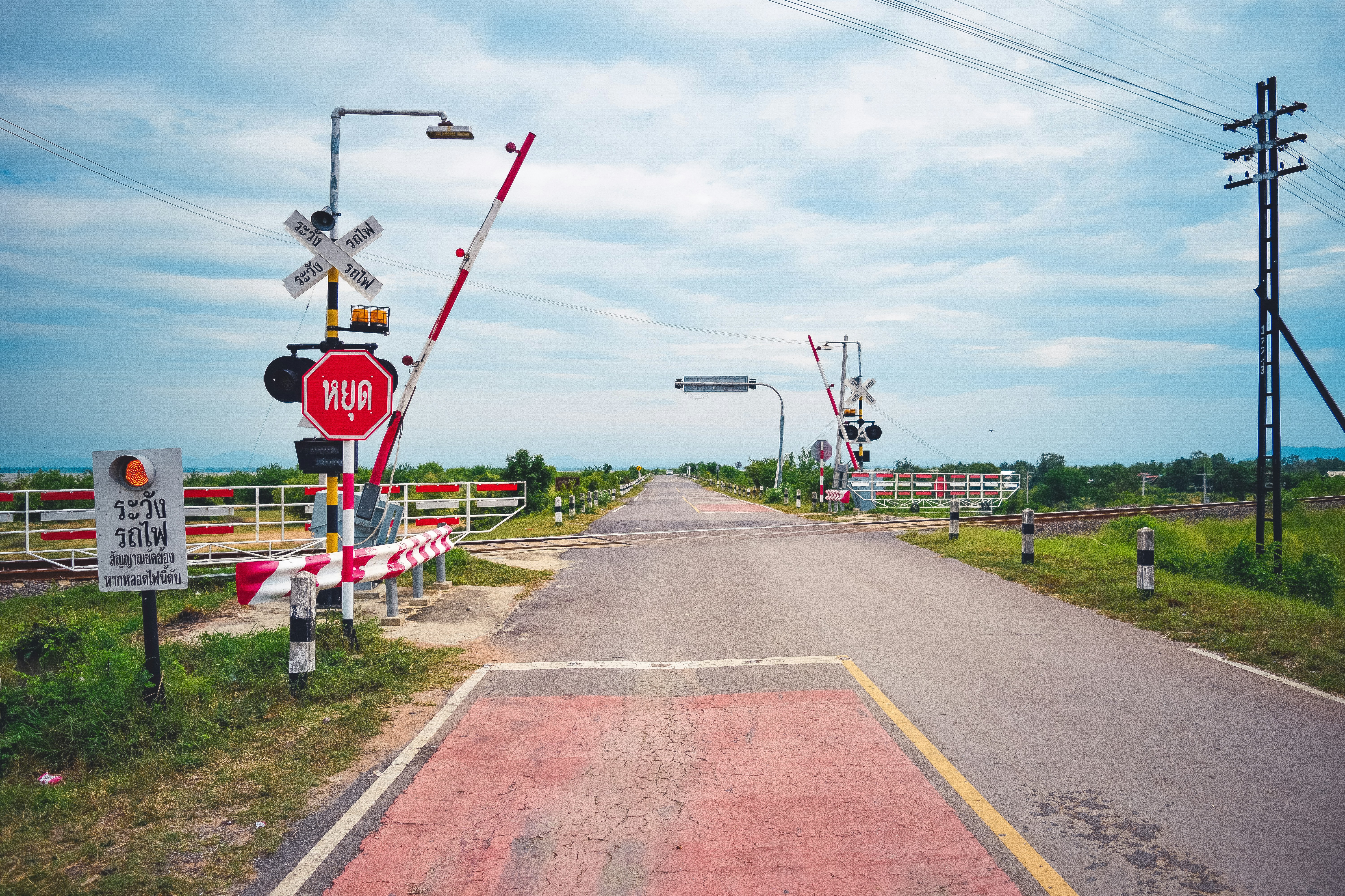 Quiet Rail Crossing: Red Stop Sign Framed by Striped Barriers on a Rural Road