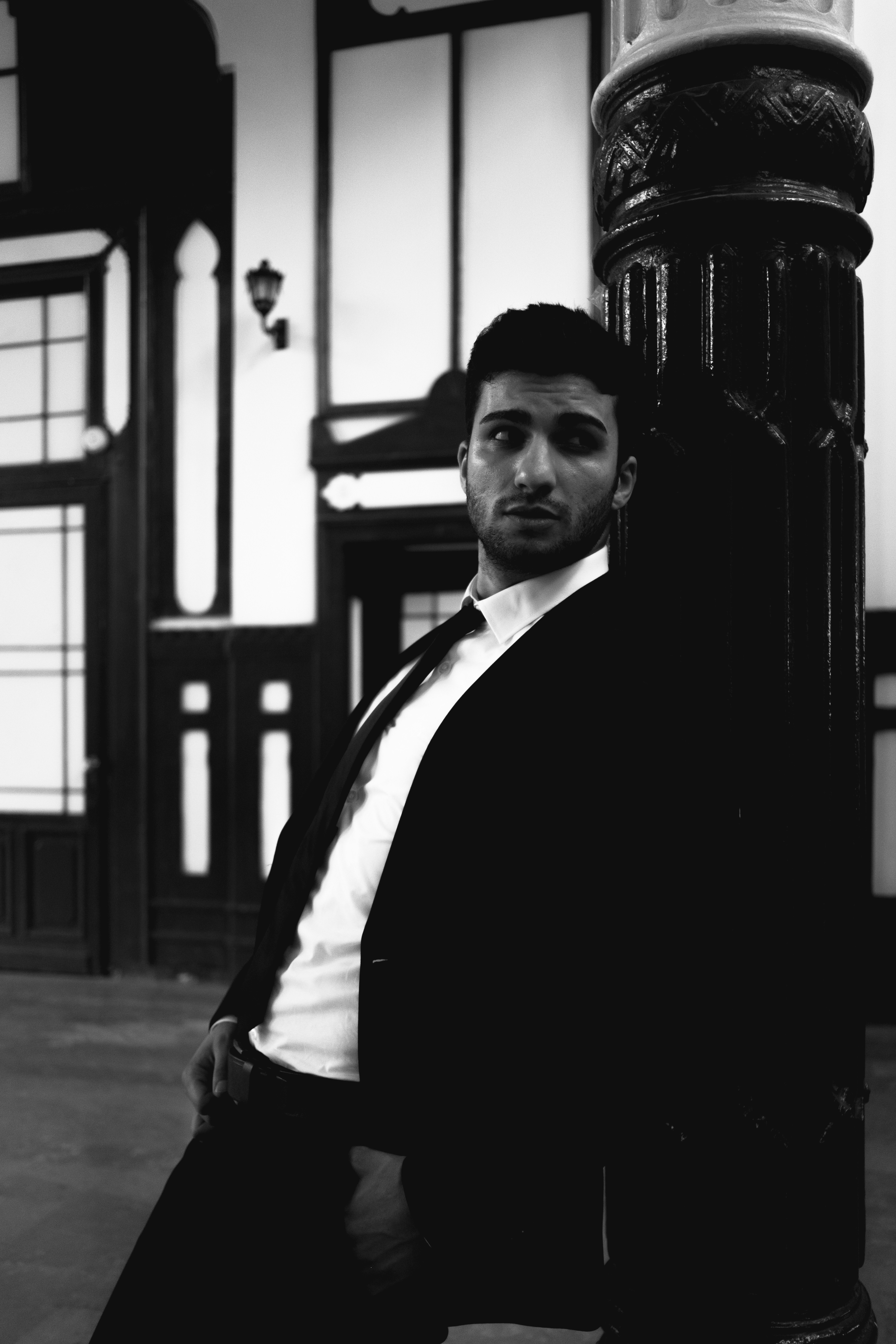 A man in a suit leaning against a pole photo – Free Portrait Image on ...