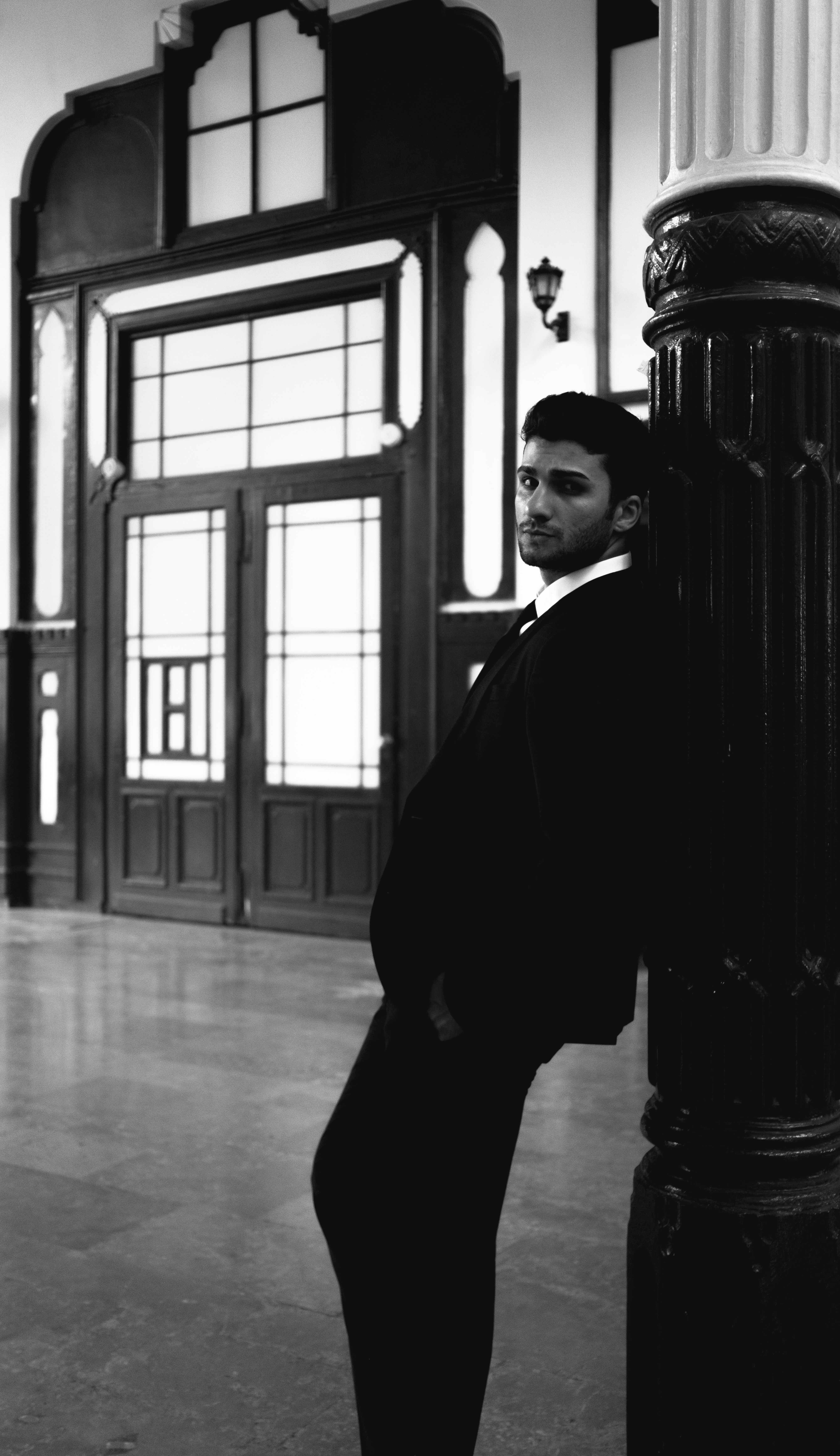 A man in a suit leaning against a pole photo – Free Portrait Image on ...