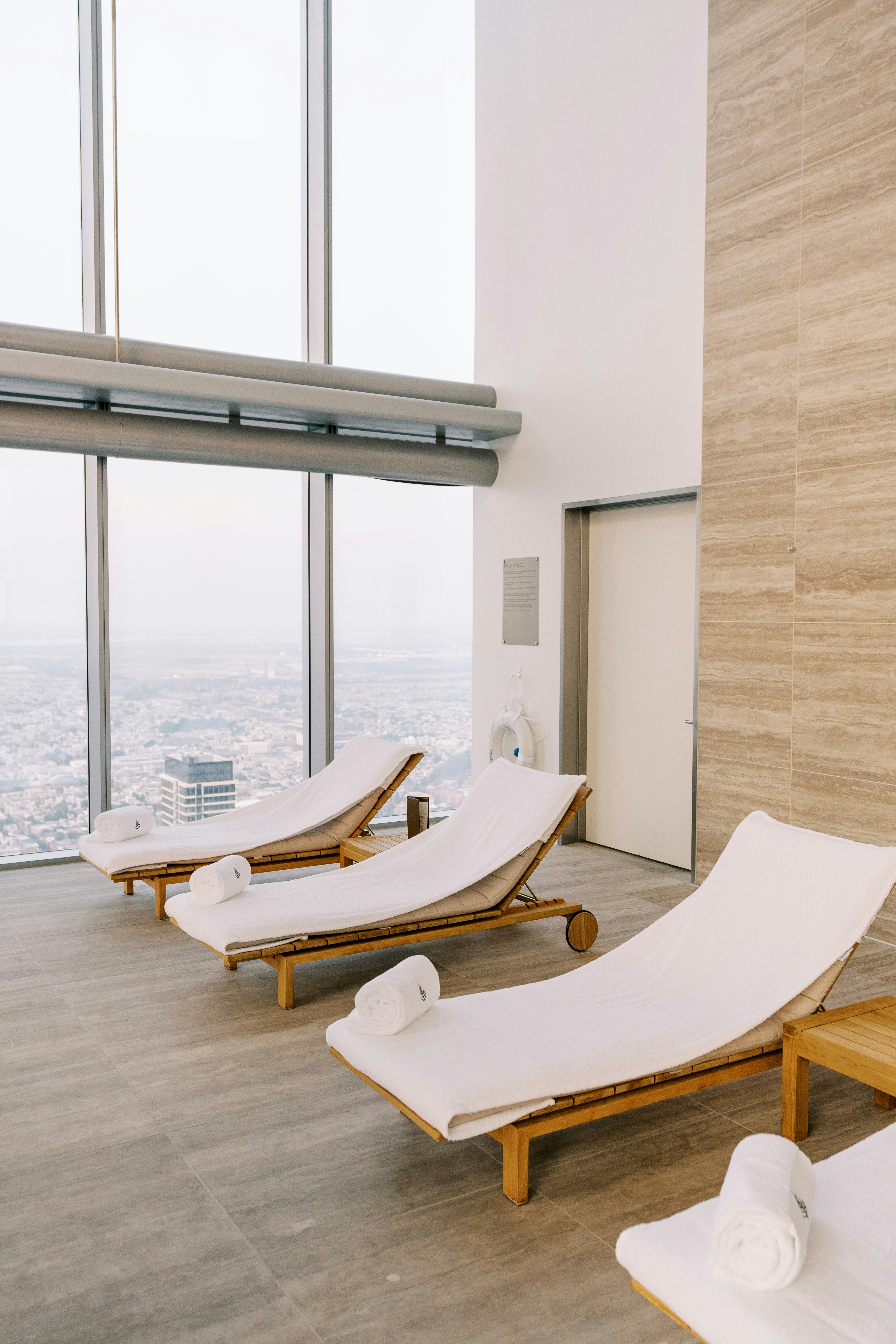 A row of chaise lounges in front of a large window photo – Free ...