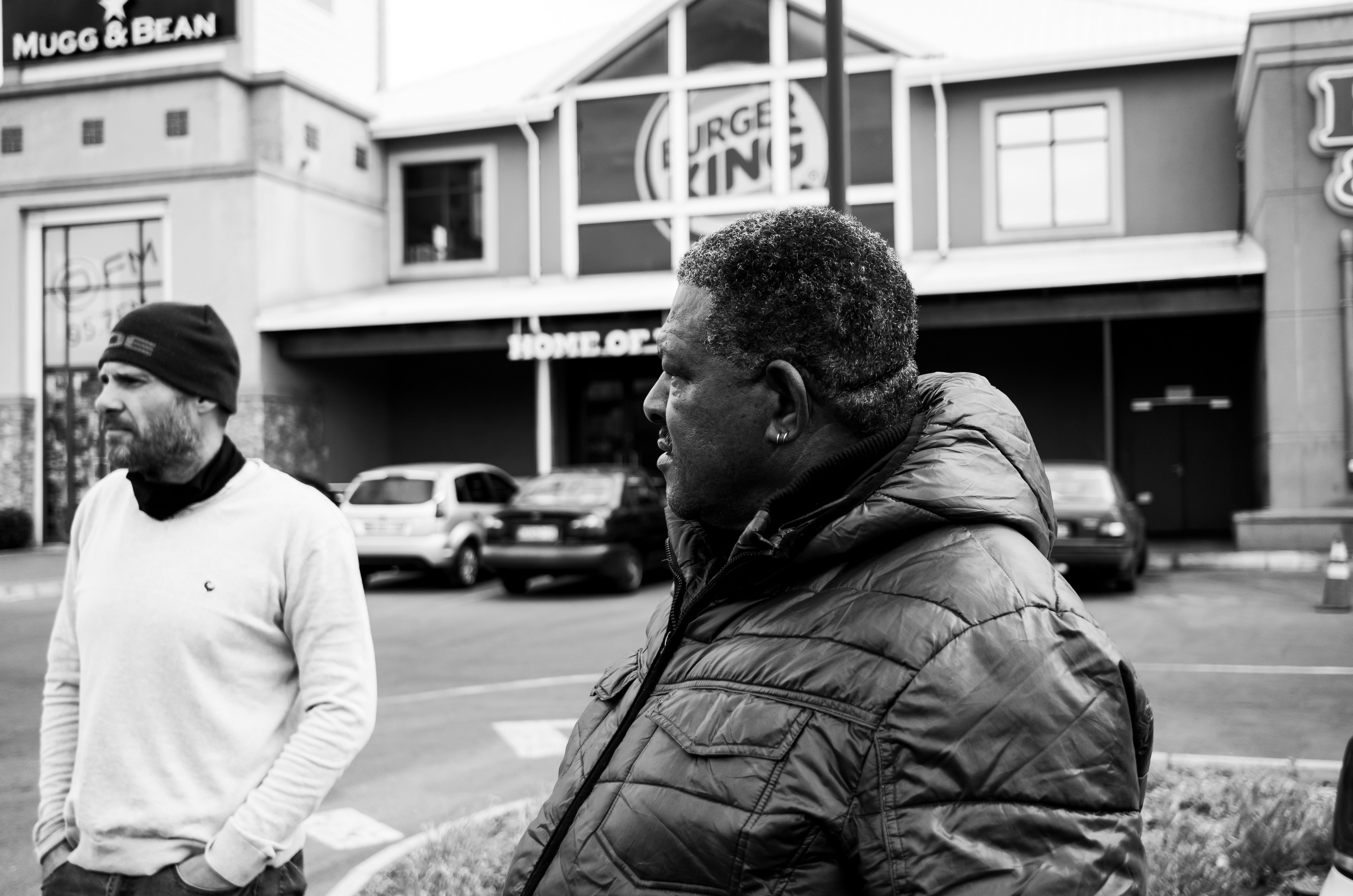 A black and white photo of two men standing in front of a building ...