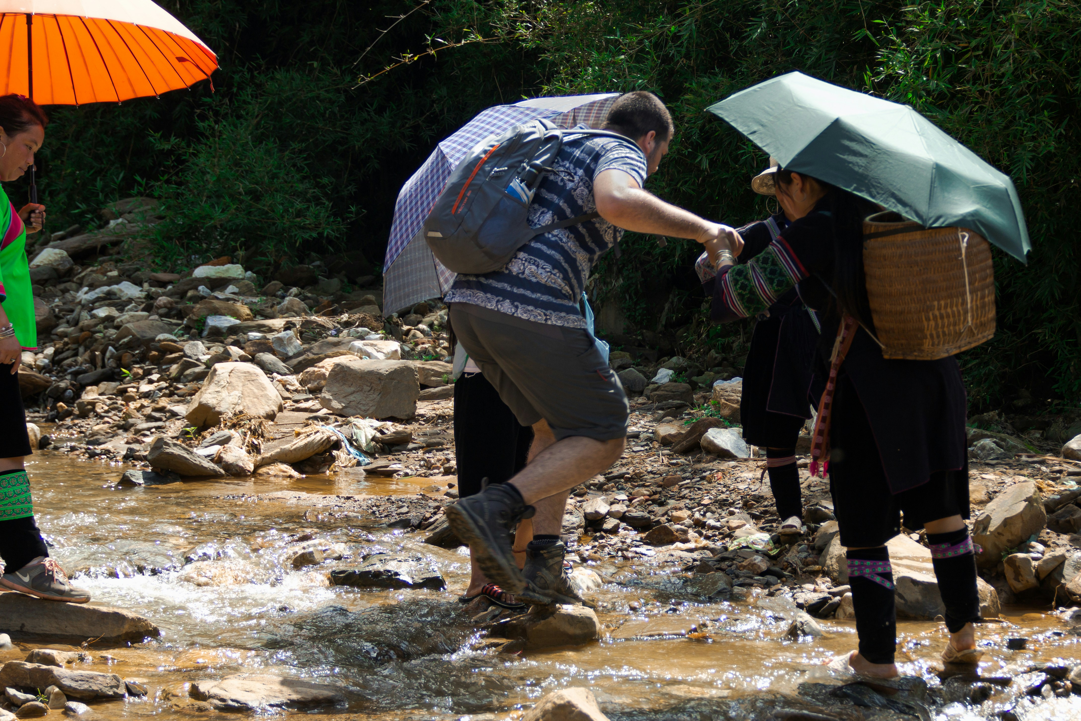 A group of people crossing a river with umbrellas photo – Free Adult ...