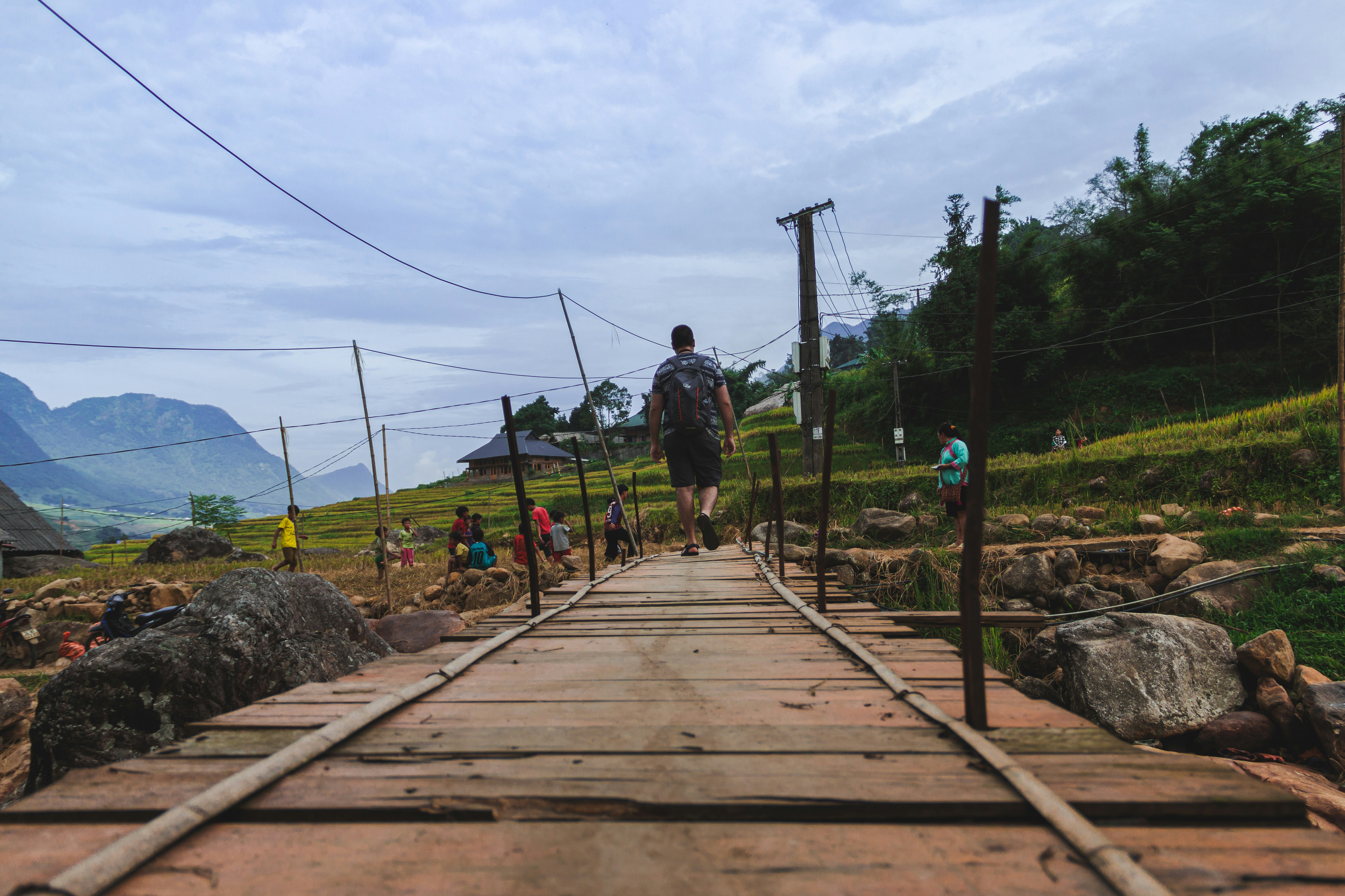 Timber Bridge Crossing: A Lone Wanderer on a Rural Path toward the Hills