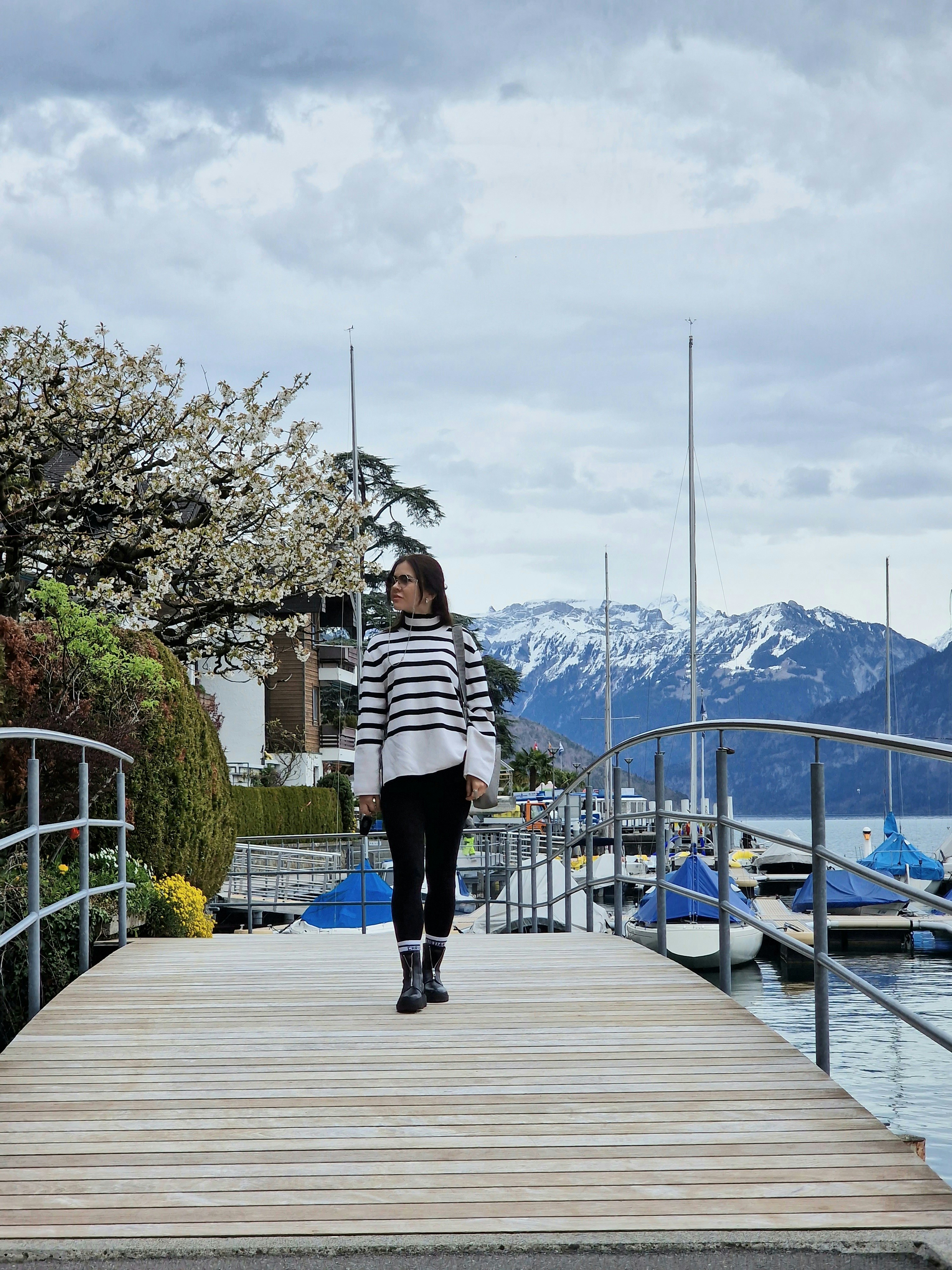 Striped Walker on a Marina Pier as Snow-Capped Alps Rise in the Distance
