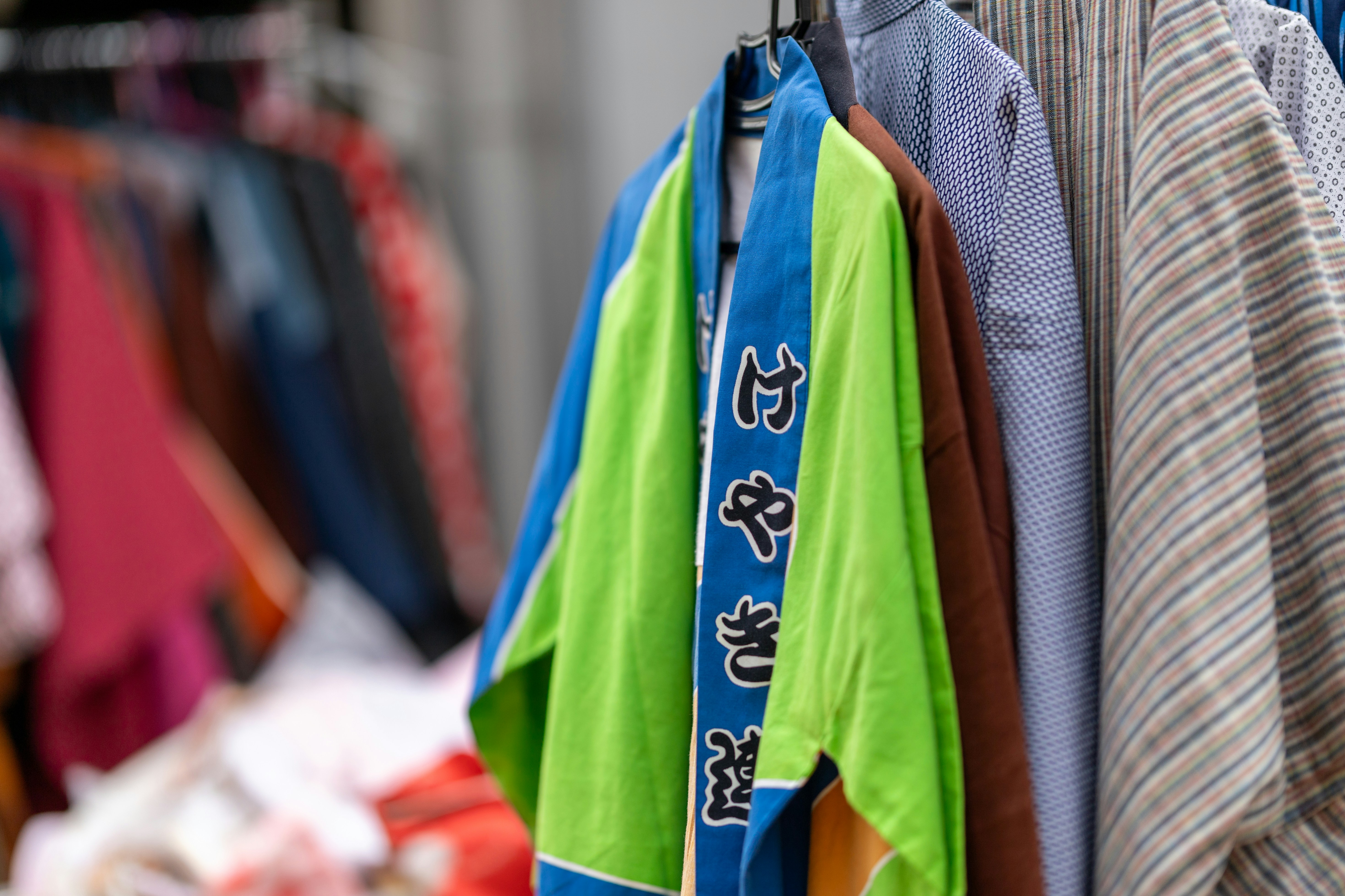 Neon-green robe with kanji on a crowded thrift rack
