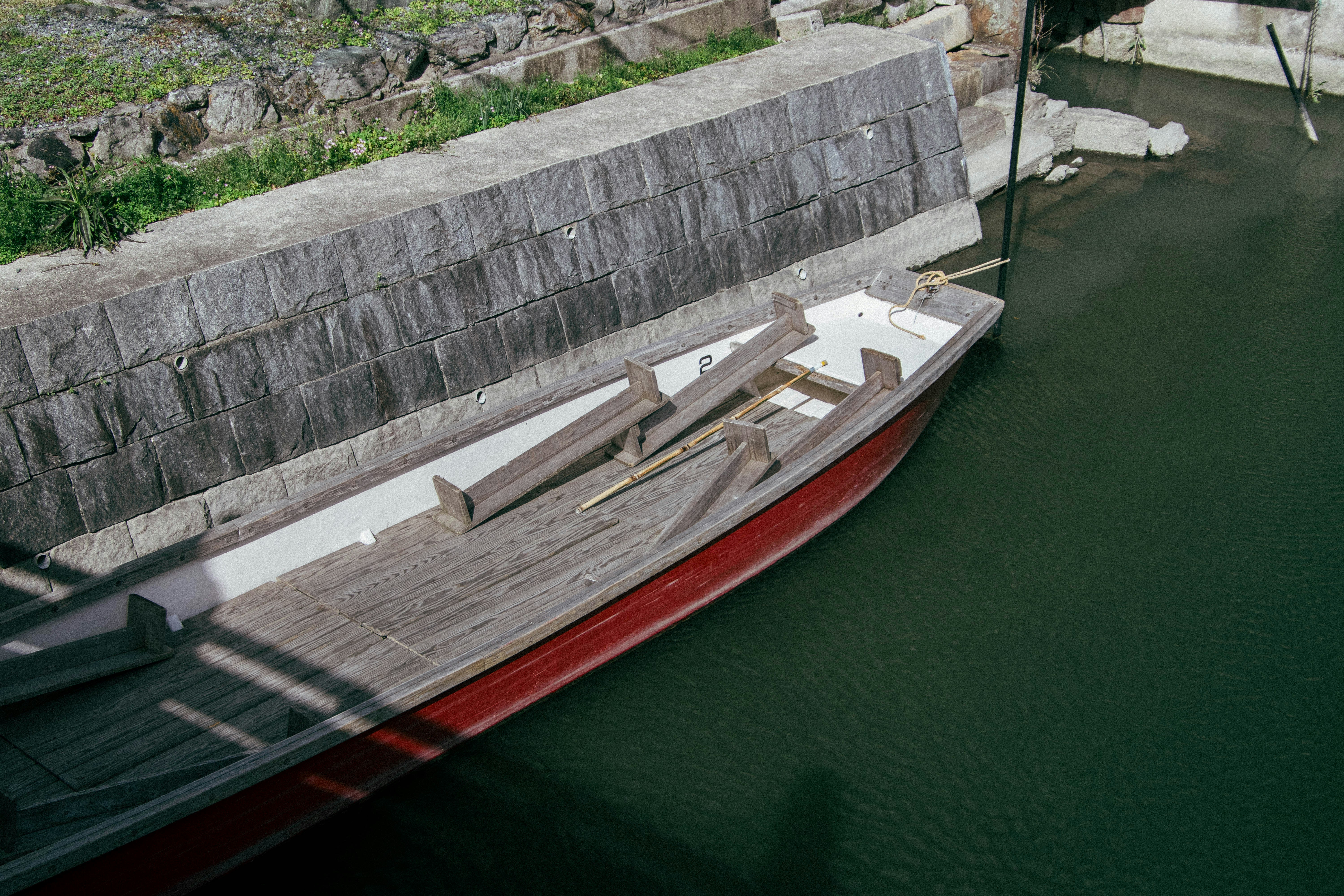 Red-Hulled Rowboat by the Stone Embankment in Quiet Canal Light