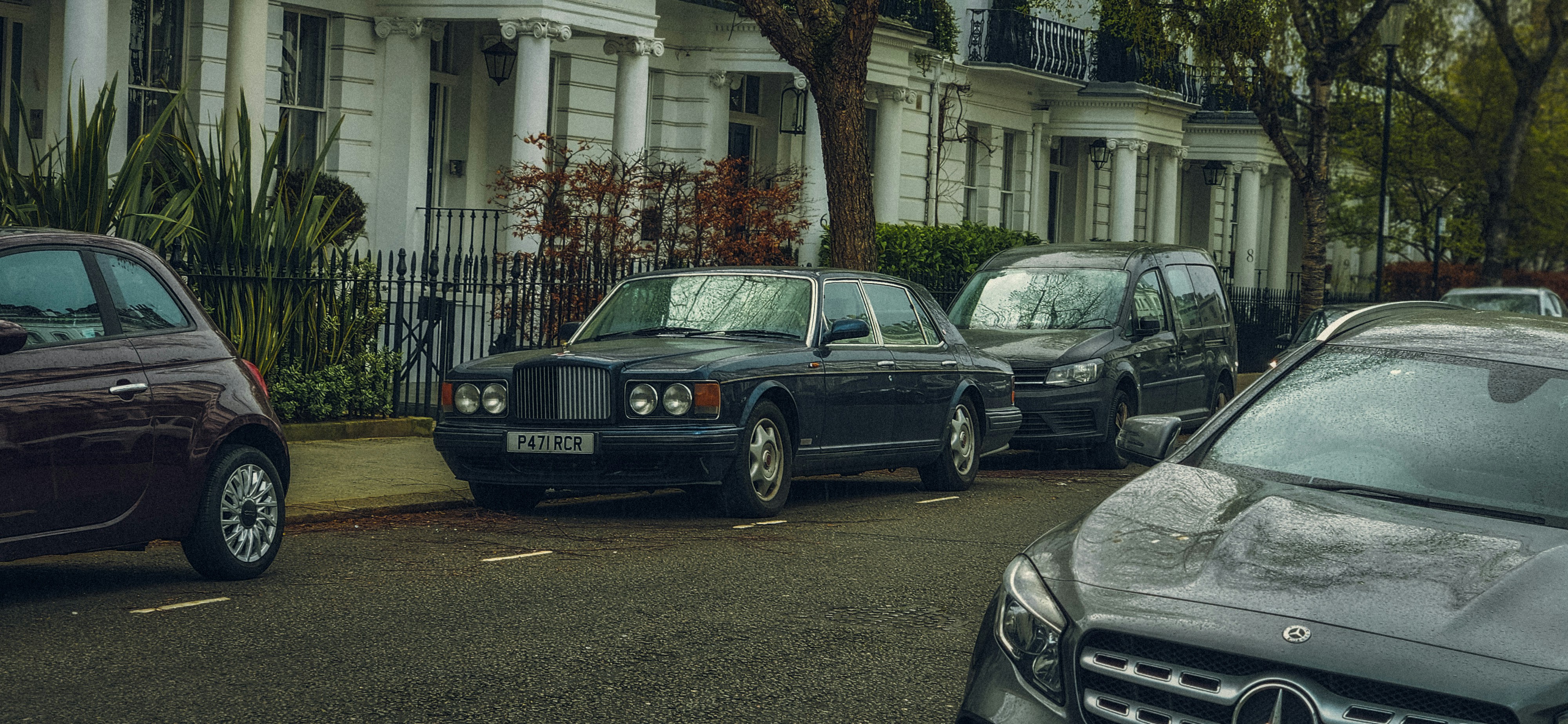 A Quiet Parade of Classic Cars Along a White-Walled Street