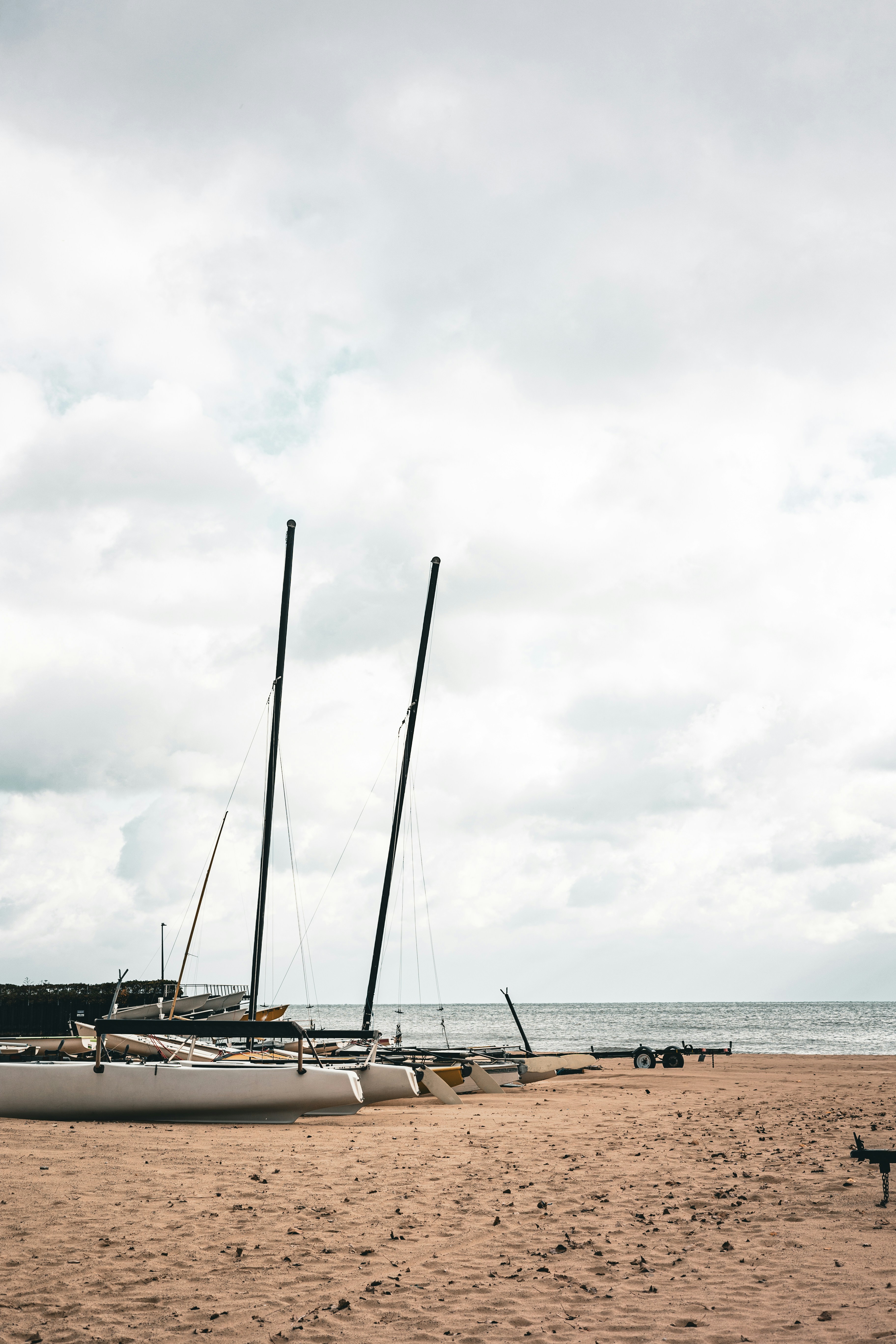 Two sailboats anchored on a sandy beach under a cloudy sky, evoking a sense of calm and tranquility.