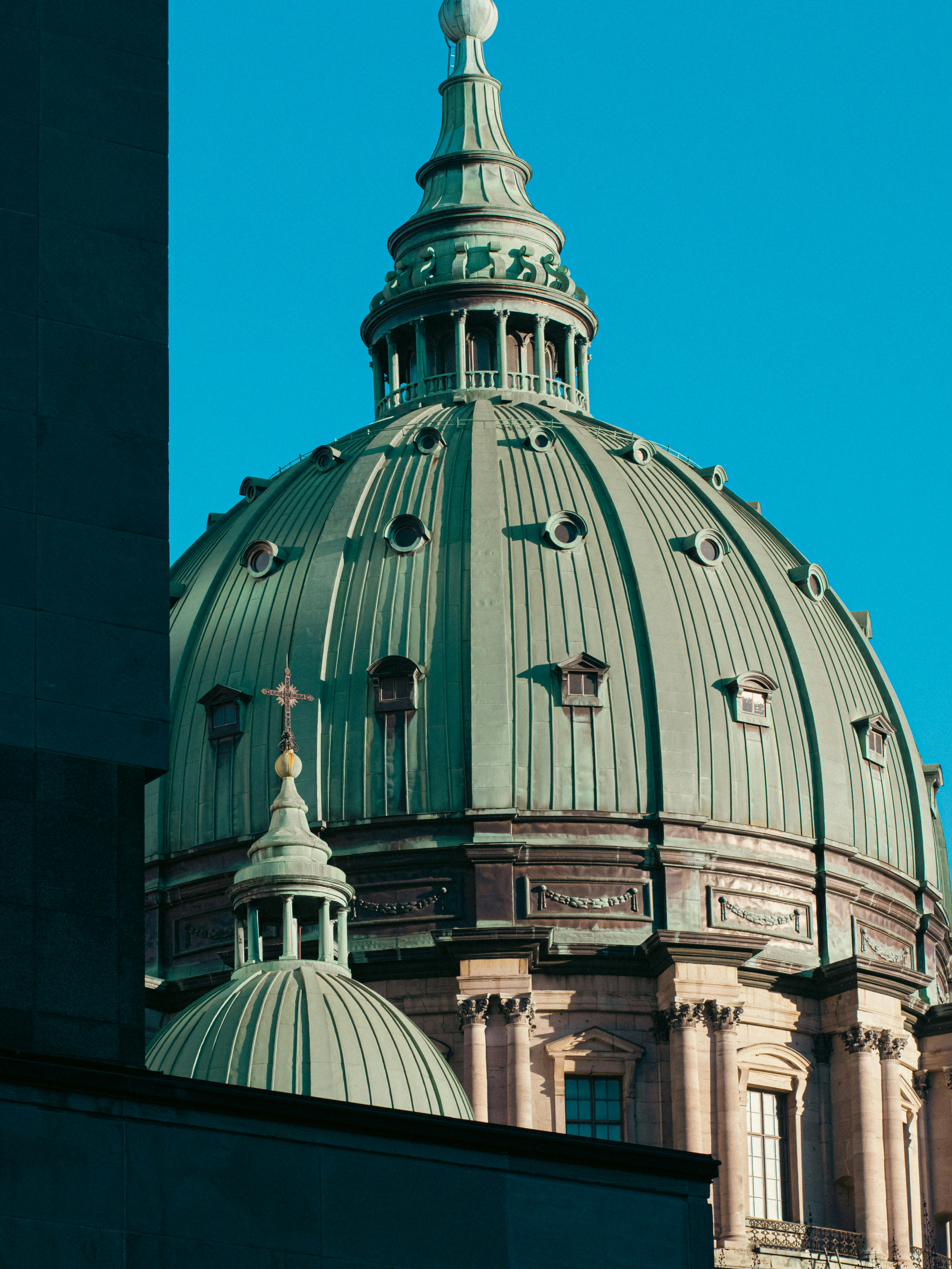 Ornate green dome of a historic building against a clear blue sky, showcasing intricate details and architectural elegance.