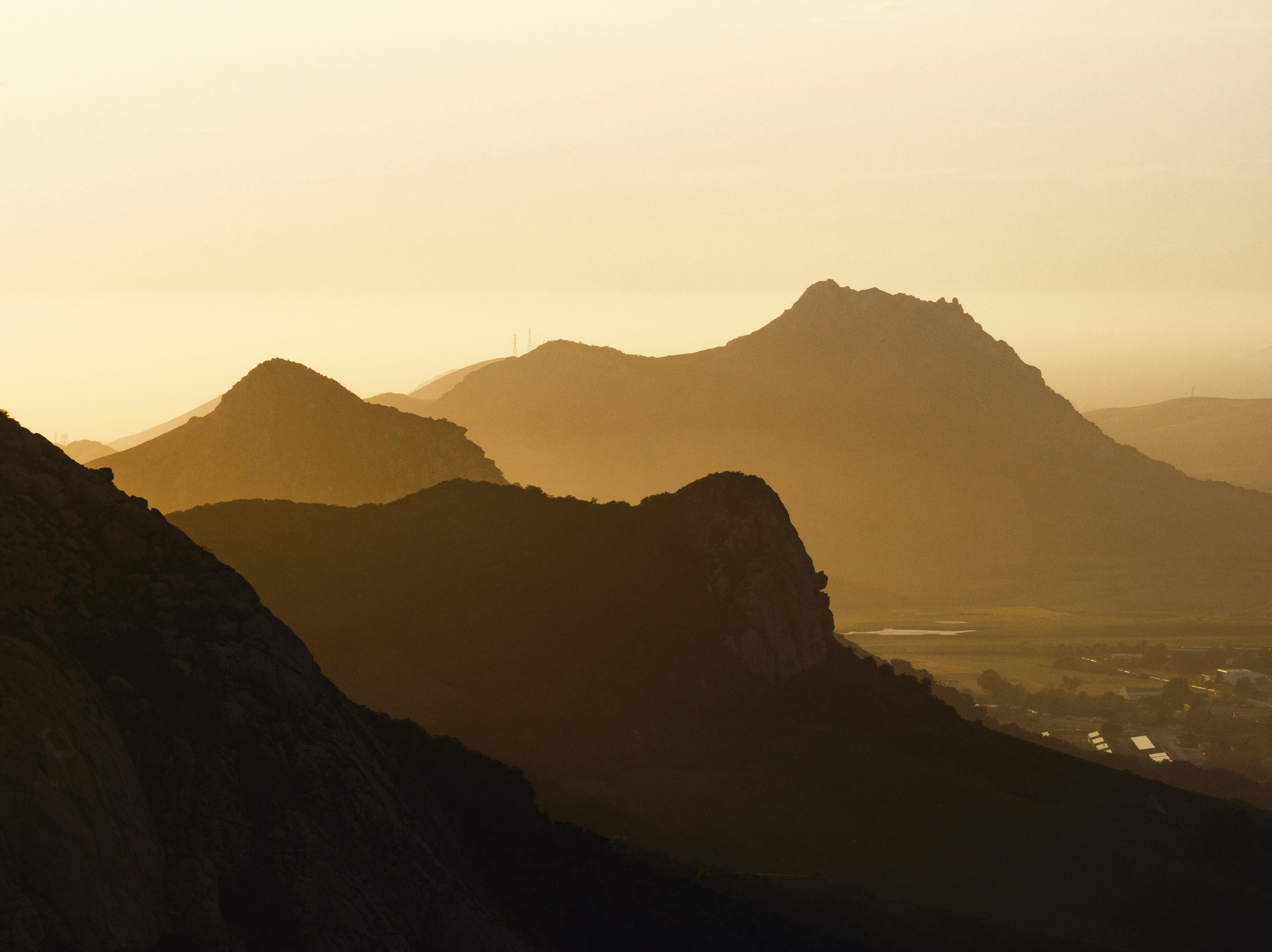 Silhouetted mountain range at sunset with warm golden hues.