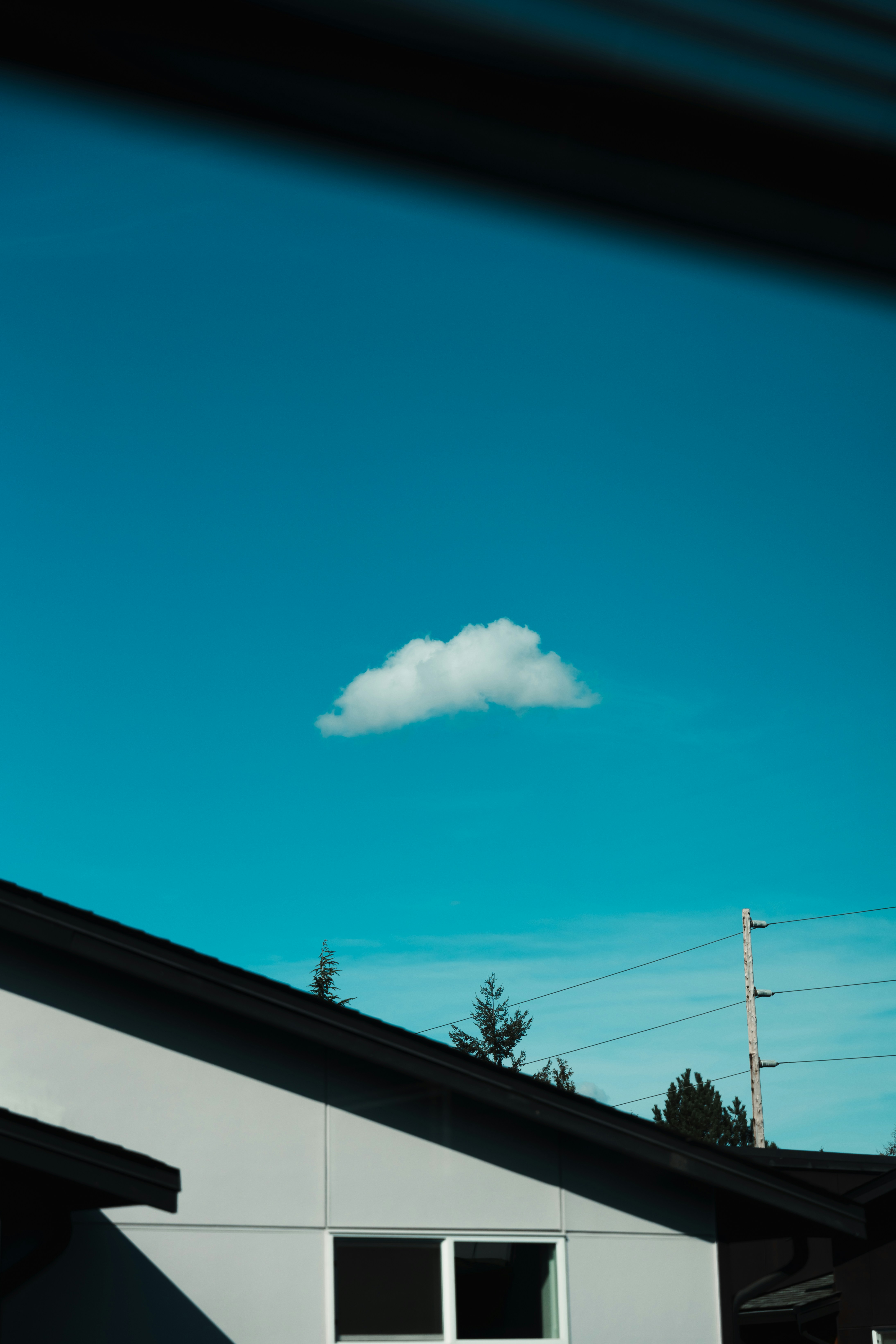 Lone Cloud Over a Teal Sky Framing a Quiet Rooftop