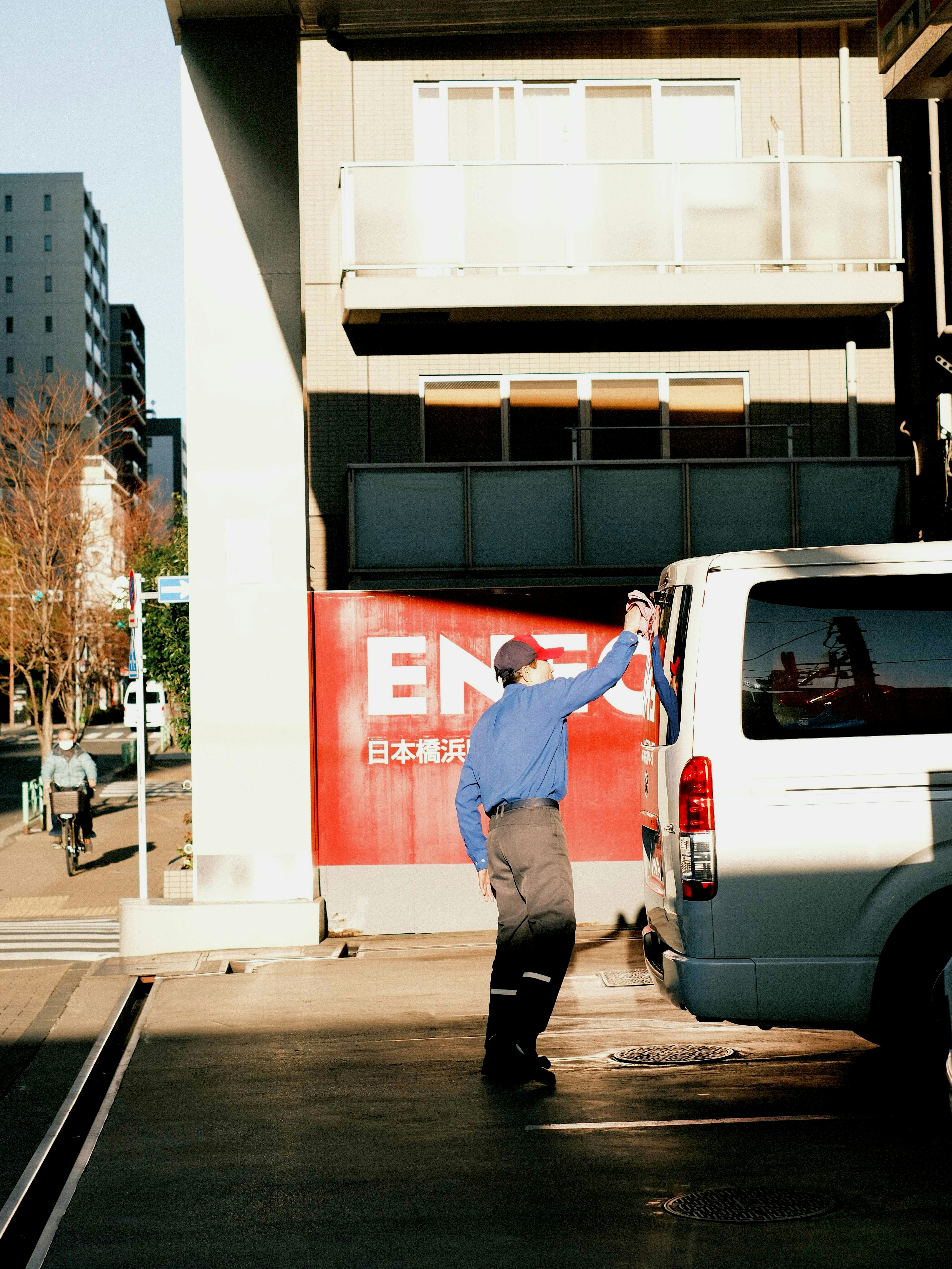 Blue Shirt at the Van: A Sunlit Urban Moment Under a Bold Red Backdrop