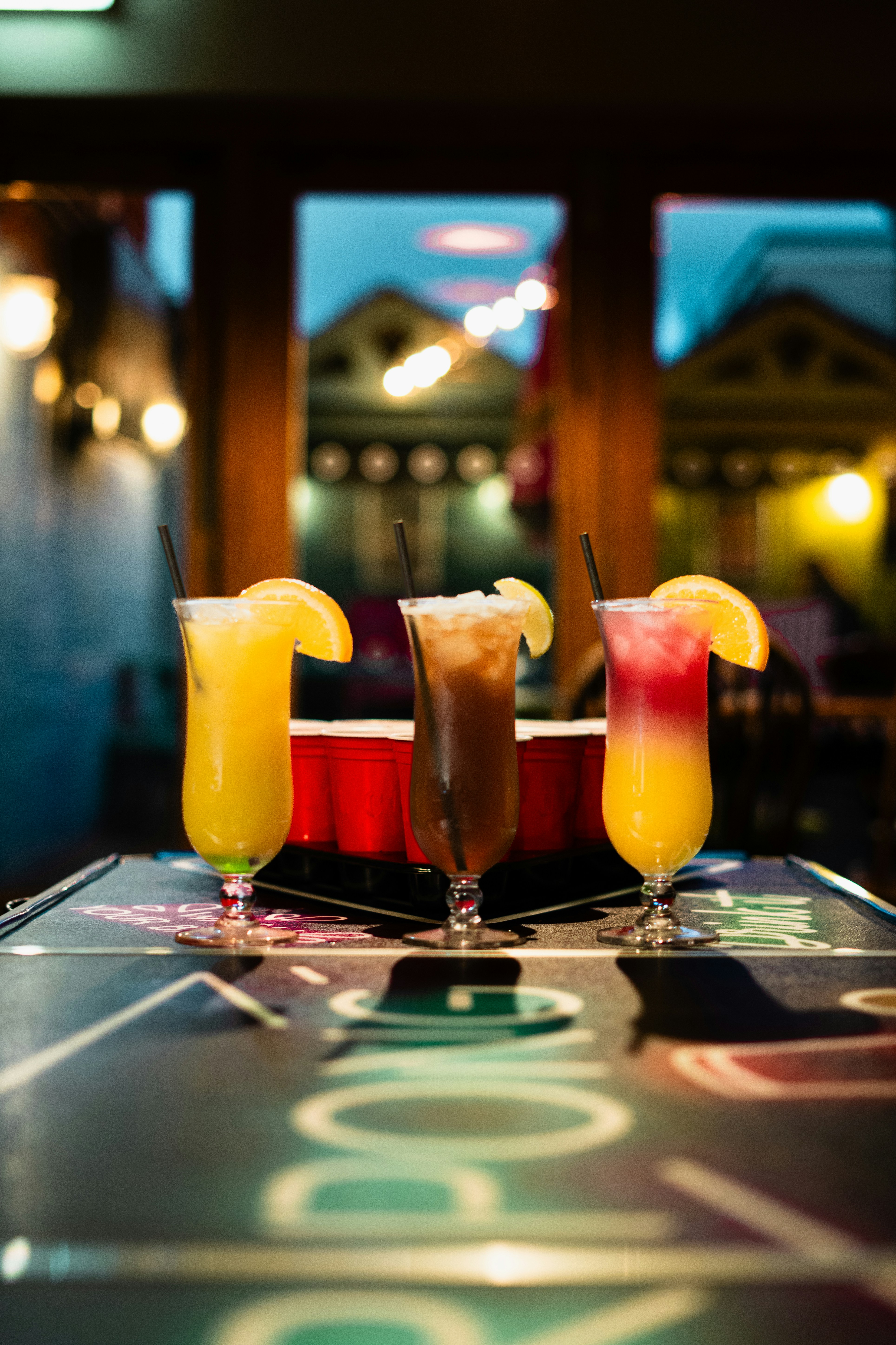 Three Tropical Beacons: Sunset-Hued Cocktails on a Dim Bar Table