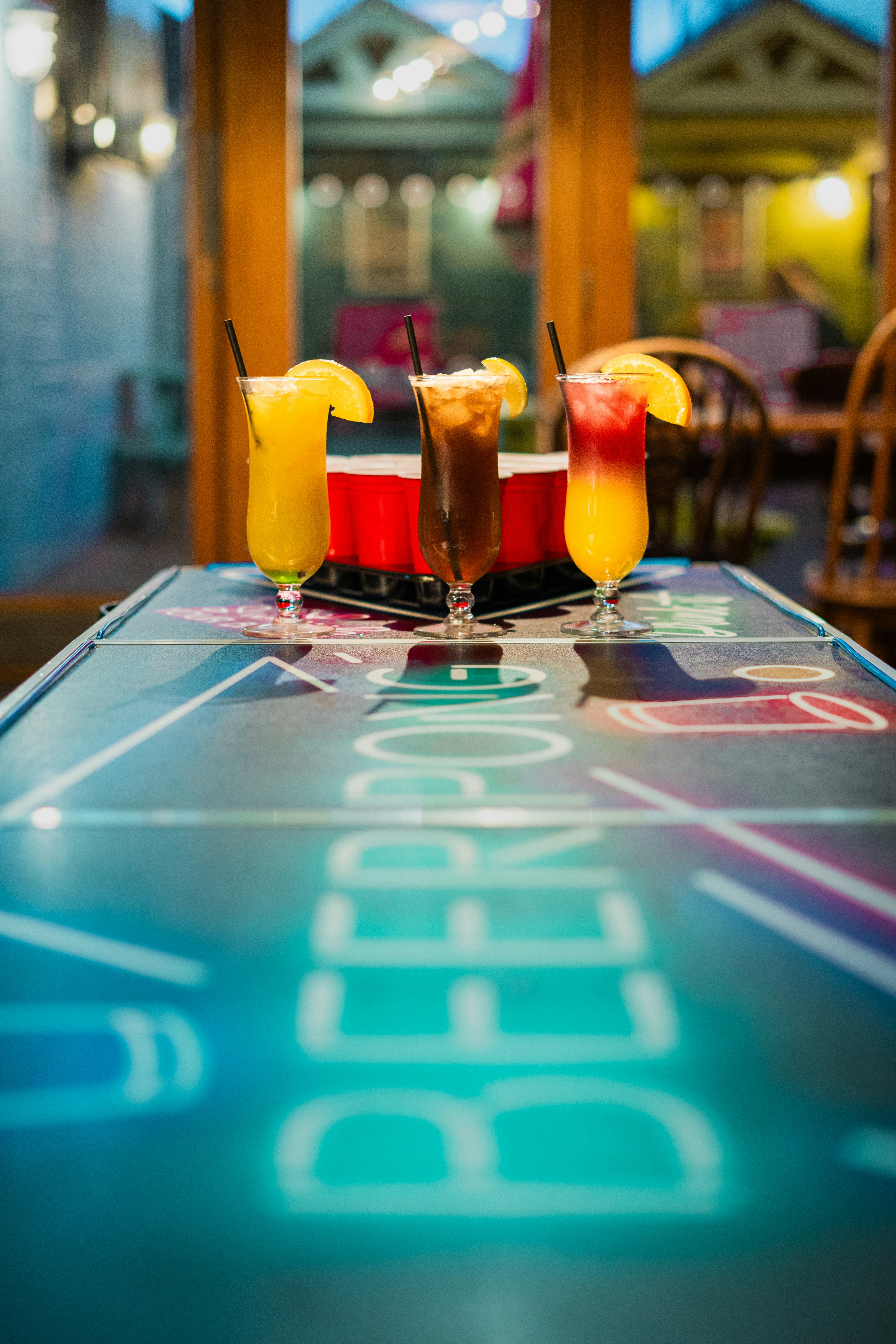 Neon Glow Trio: Tropical Cocktails Framed by a Glossy Bar