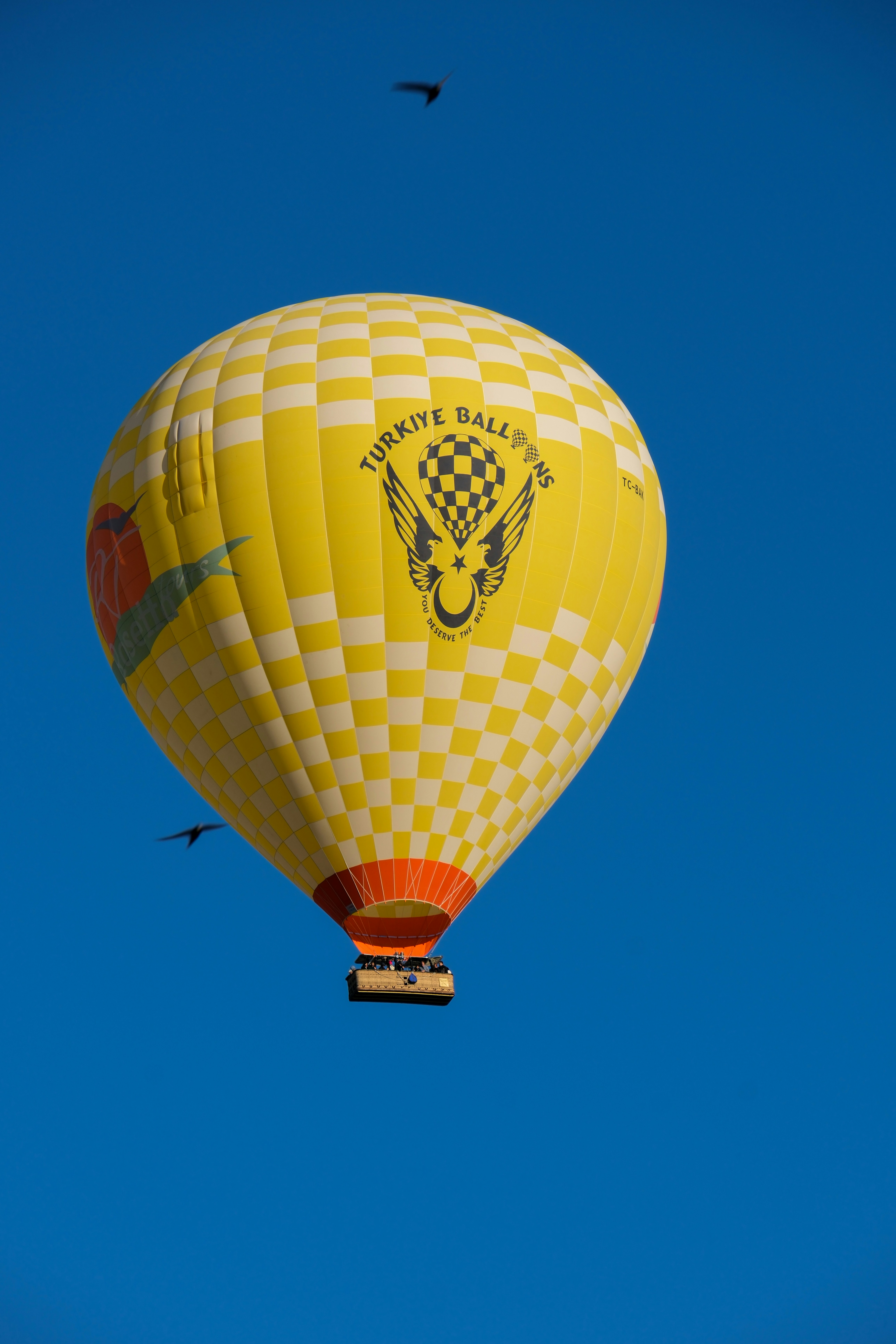 A yellow and white hot air balloon flying through a blue sky photo ...