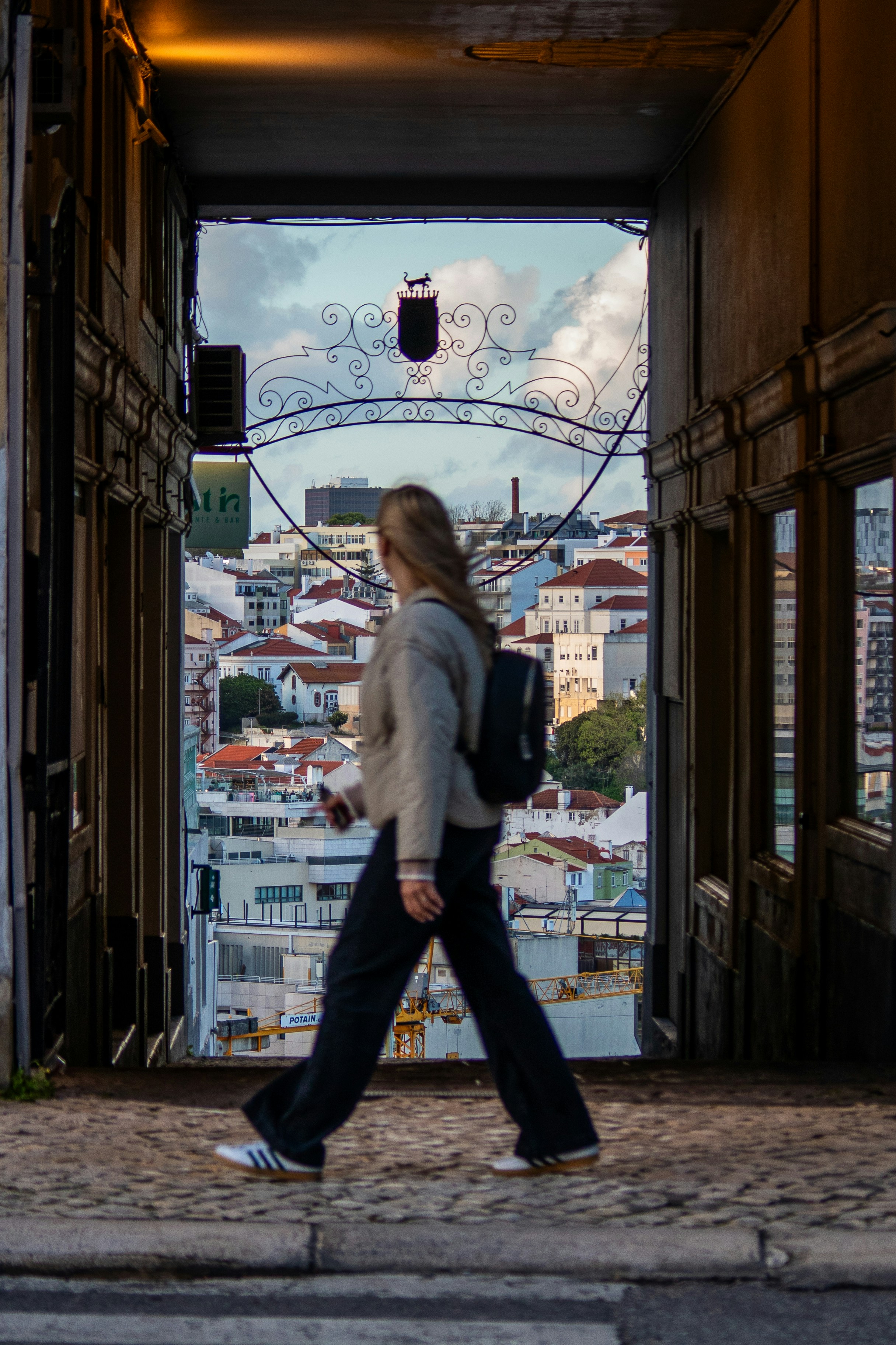a woman walking down a street next to a tall building