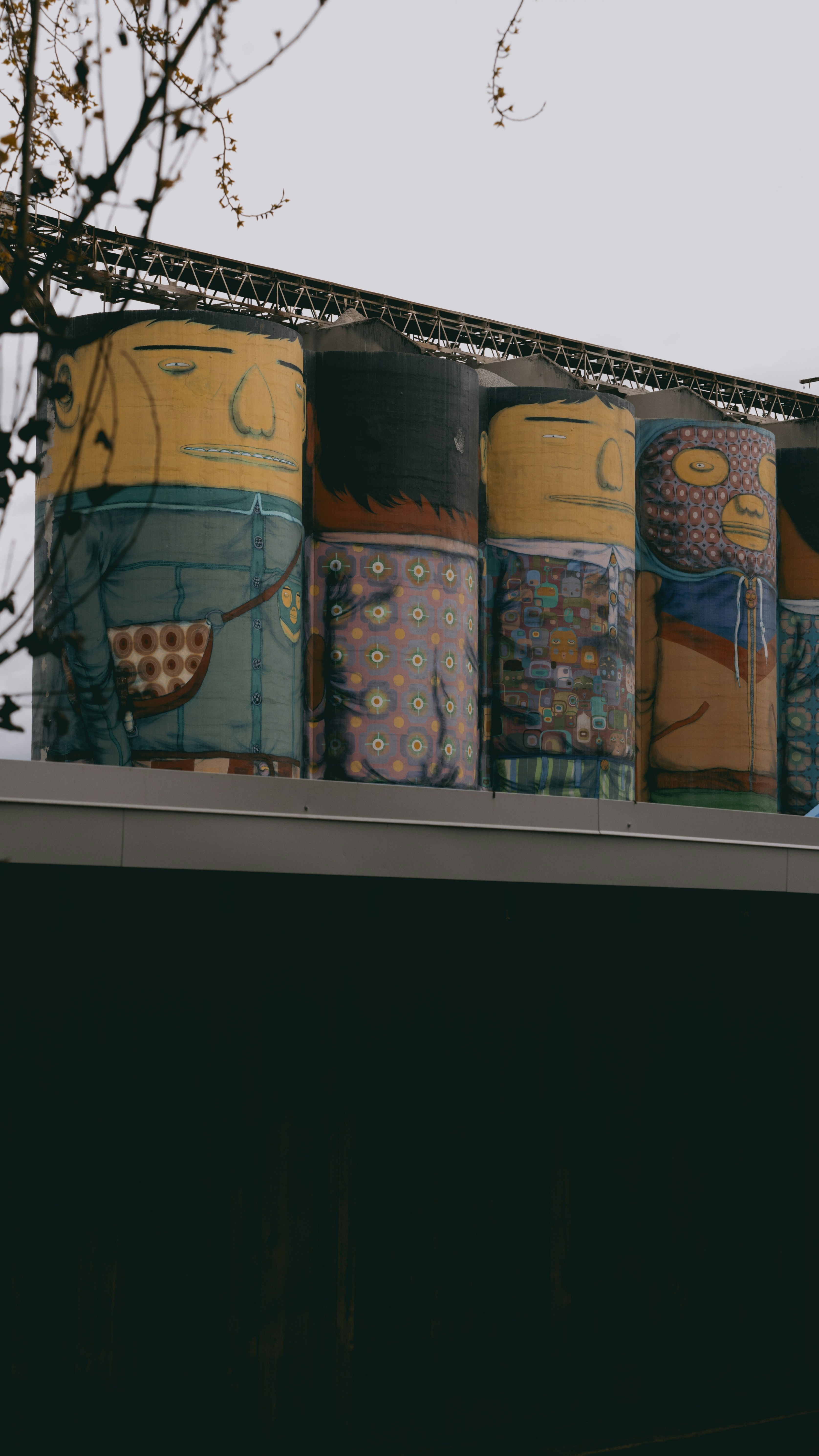 Cylinder Portraits: A Row of Cartoon Murals Crown an Industrial Roof