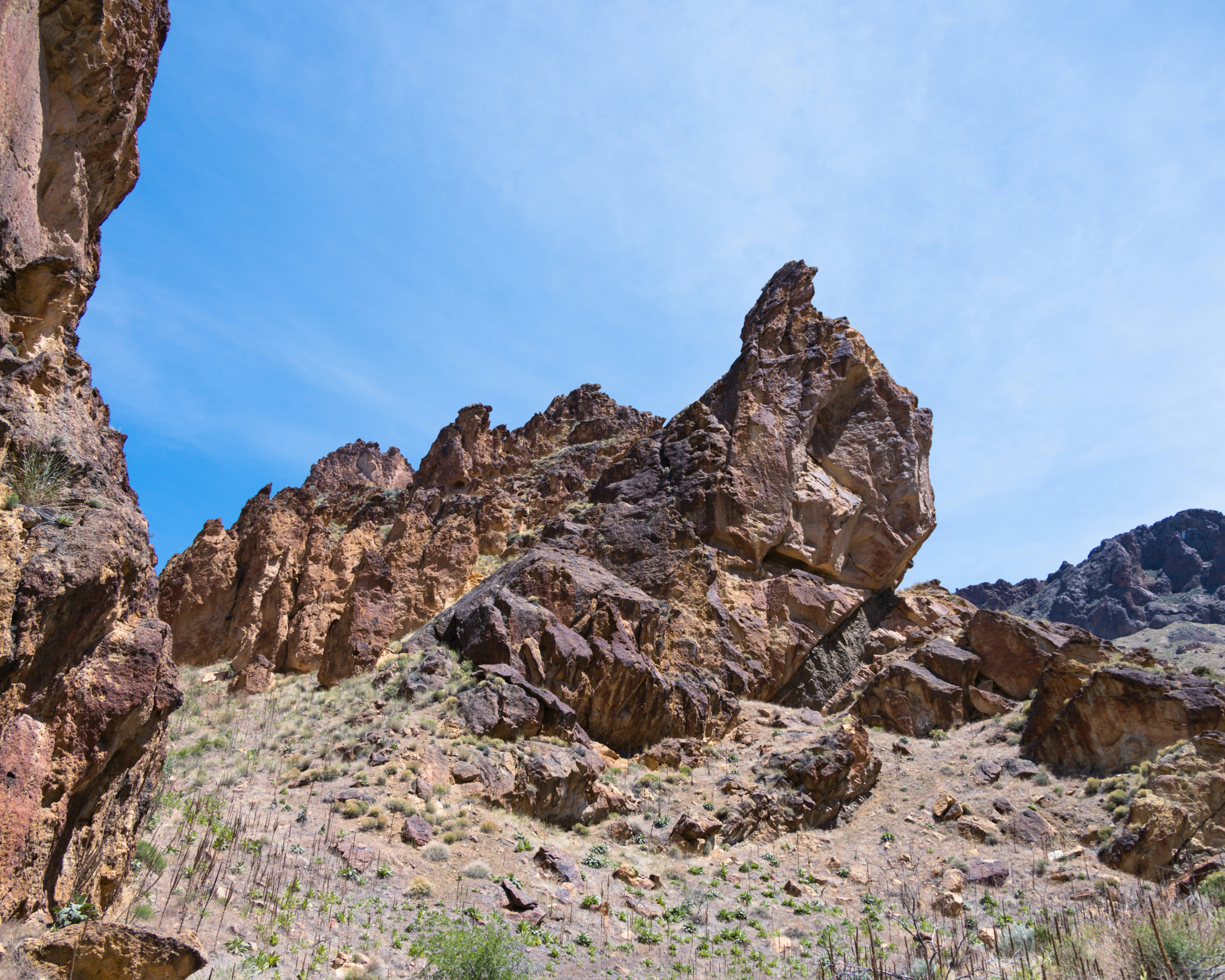 A rocky mountain side with a blue sky in the background photo – Free ...